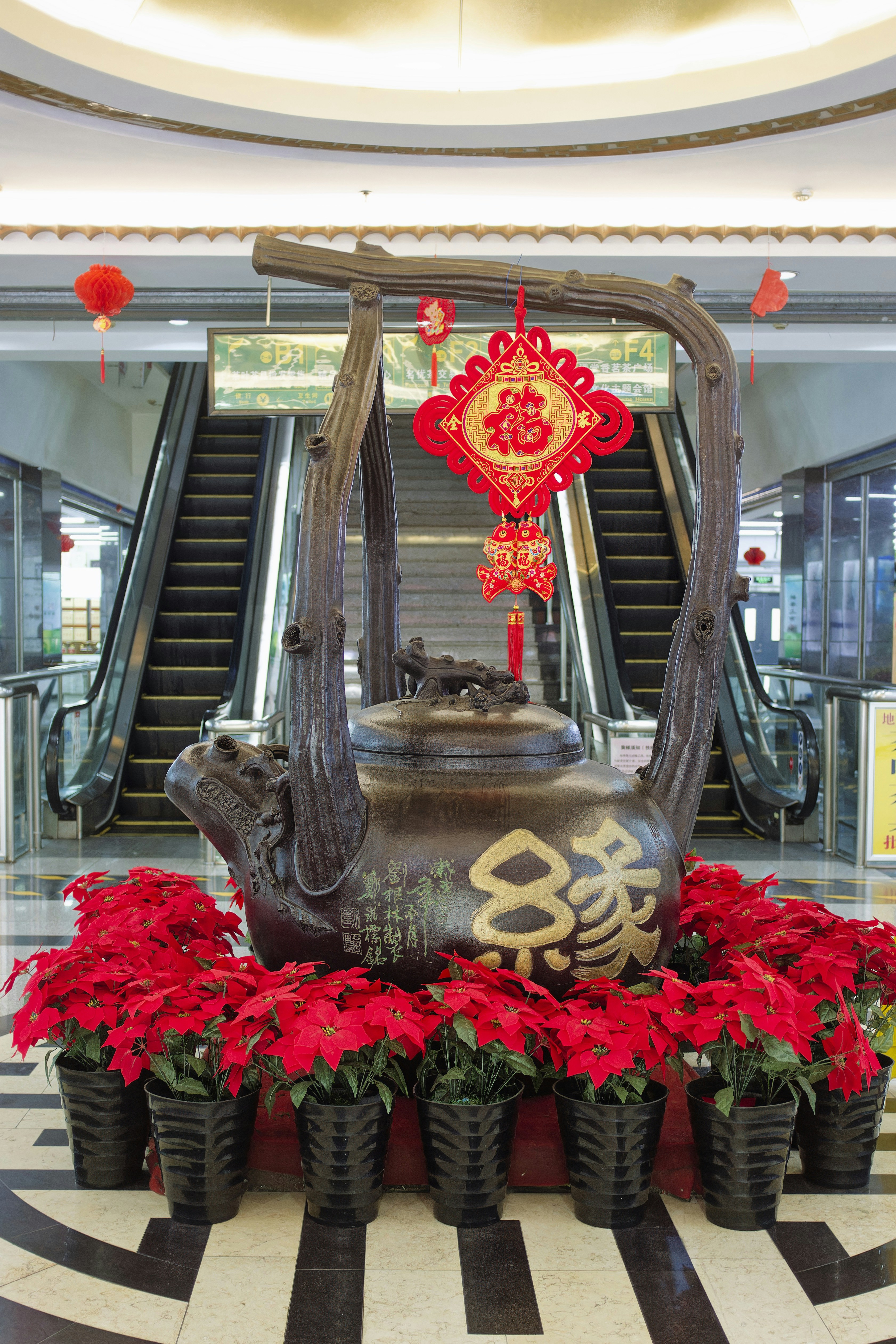 Bronze Teapot Chronicle: A Festive Centerpiece Framed by Red Ornaments in a Shopping Mall Atrium