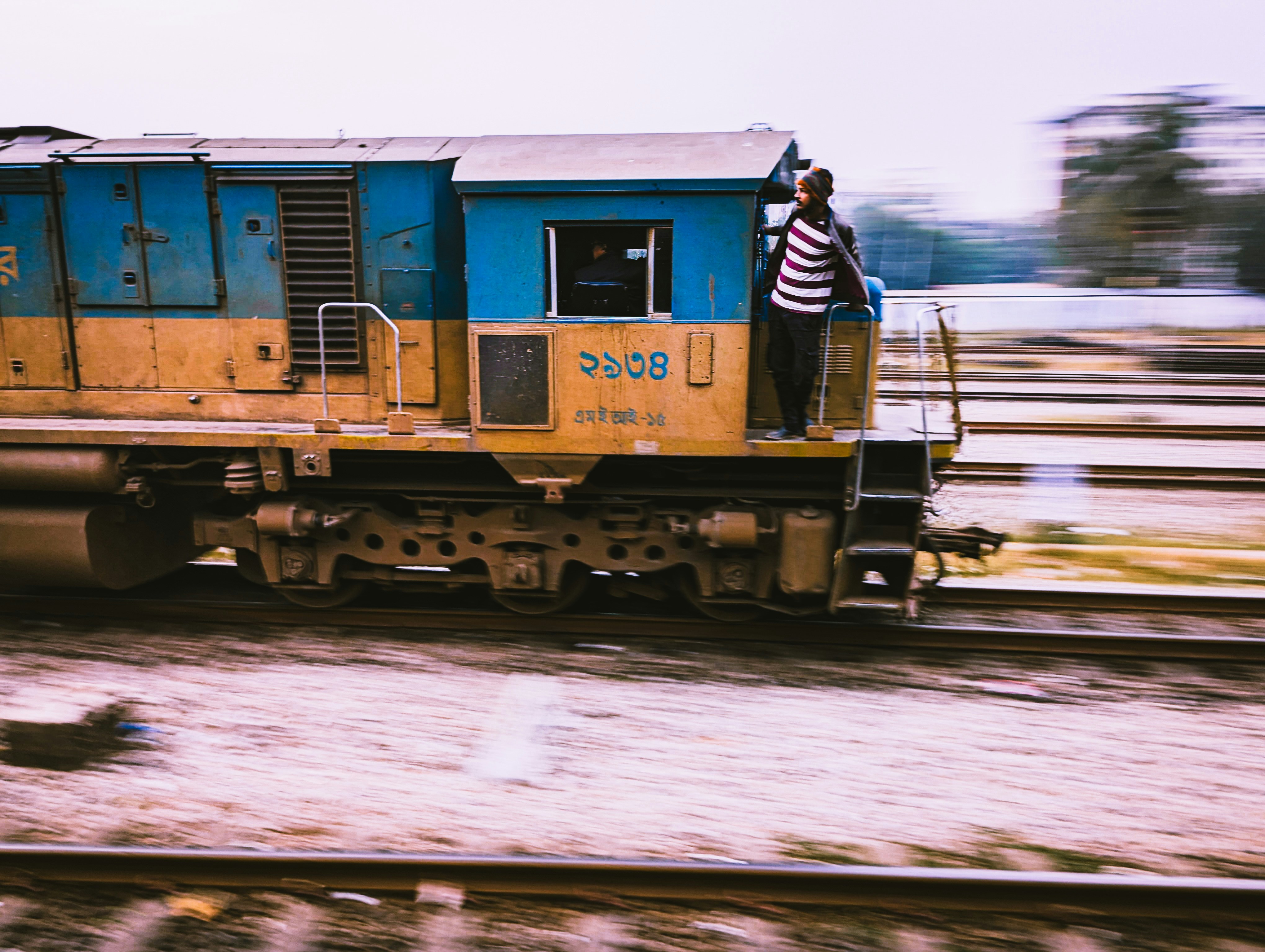 A man is standing on the side of a train photo – Free Railway Image on ...
