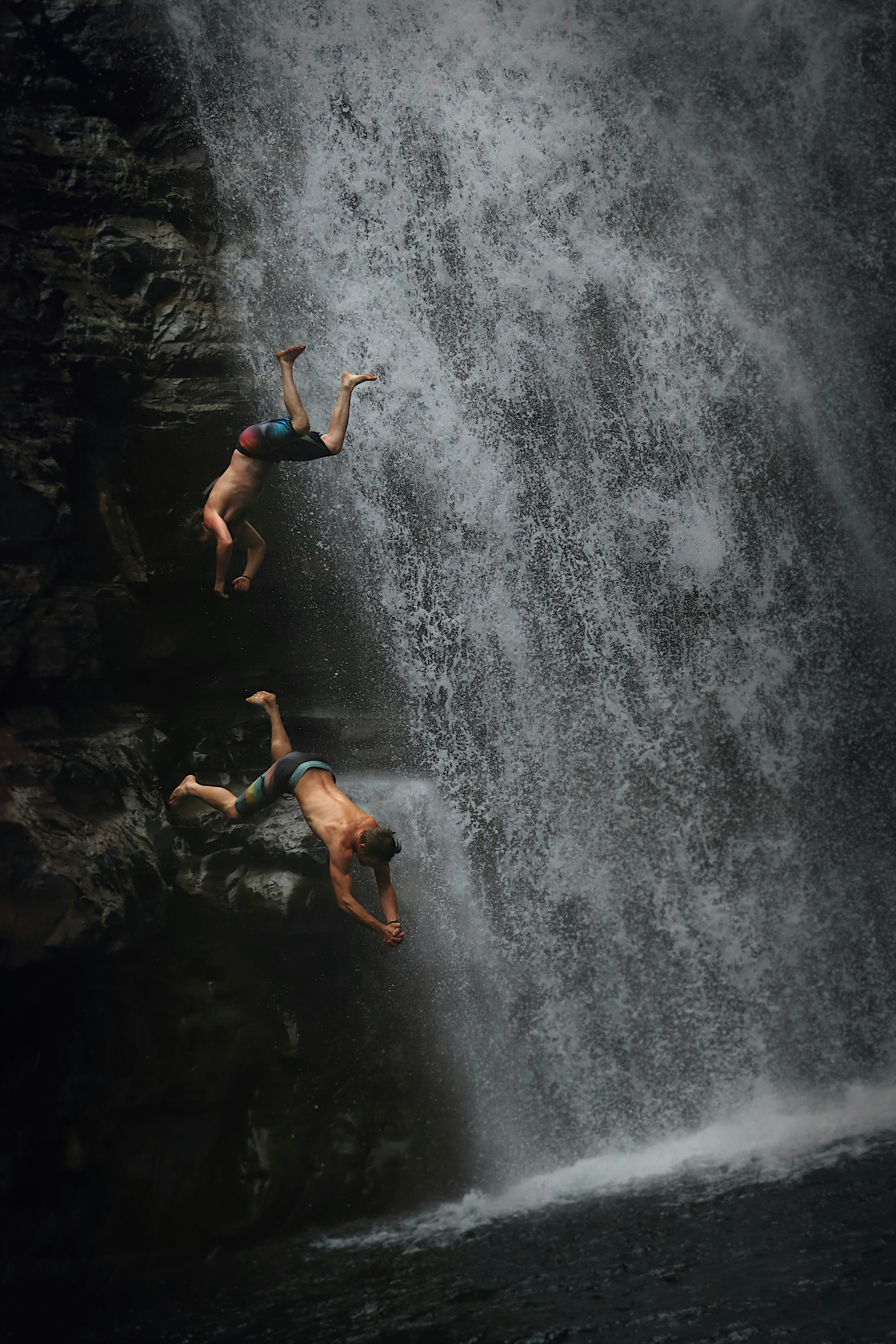 Two people jumping off a waterfall into a body of water photo – Free ...