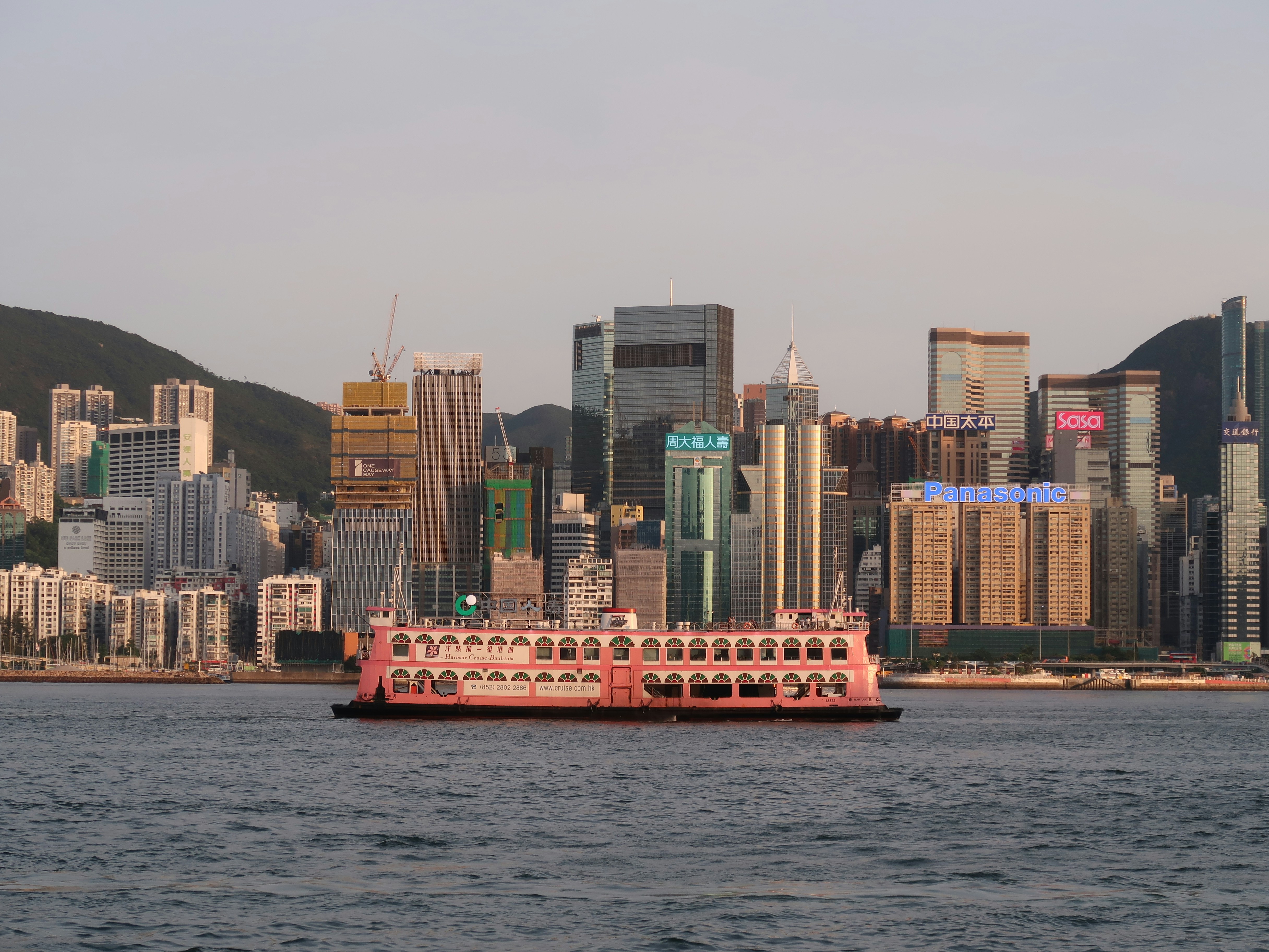 Pink Ferry Gliding Through Victoria Harbour Against a Glass-Clad Skyline