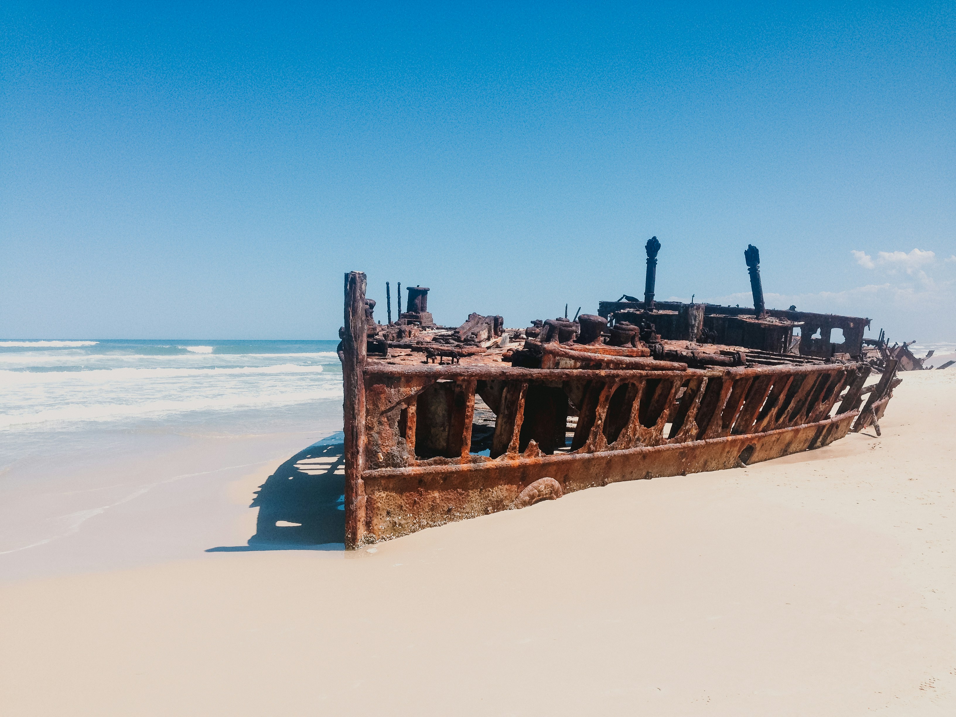 Rust-Stained Wreck on a Quiet Beach: A Sunlit Sentinel in Sand