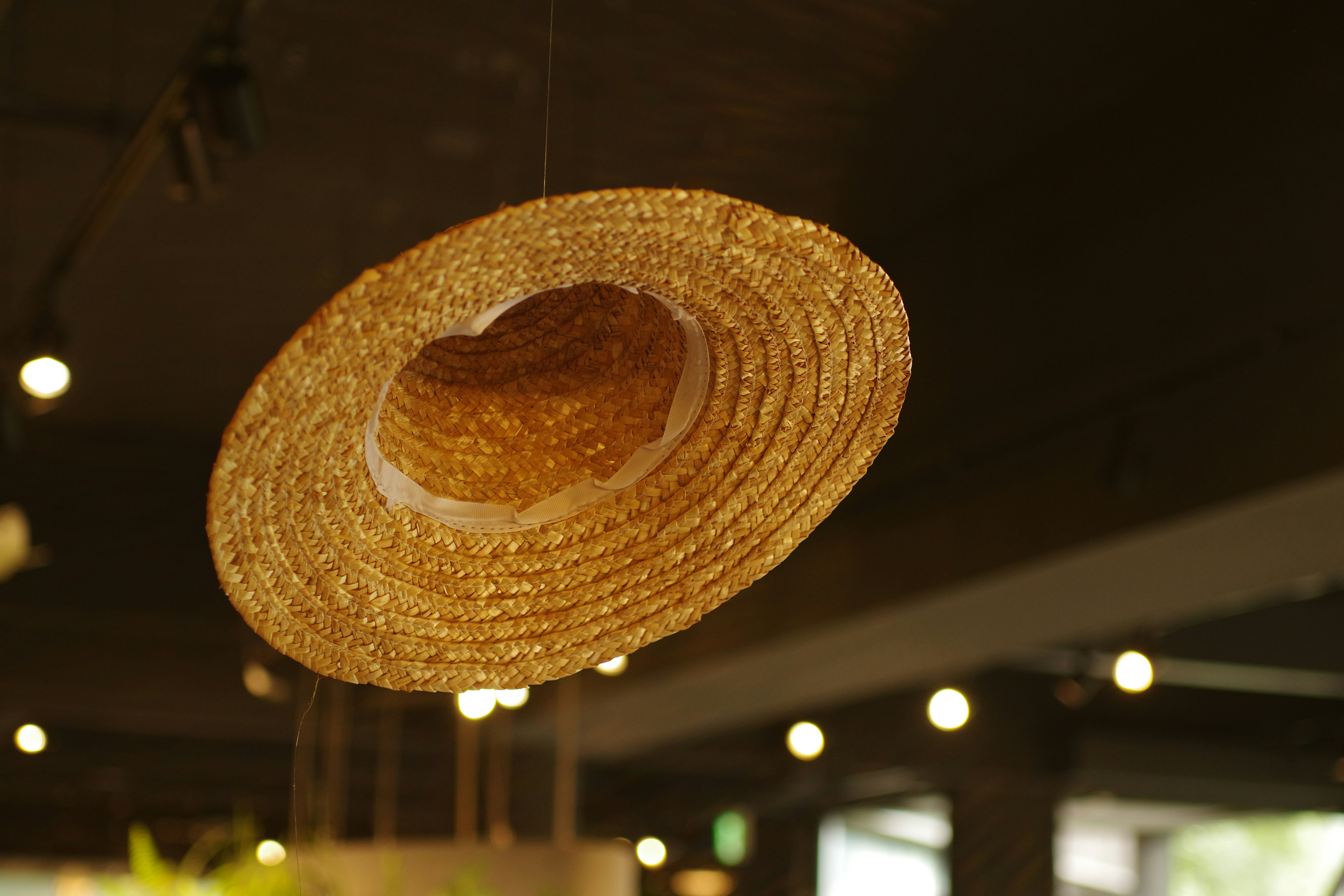 A straw hat hanging from the ceiling of a restaurant photo – Free Lamp ...