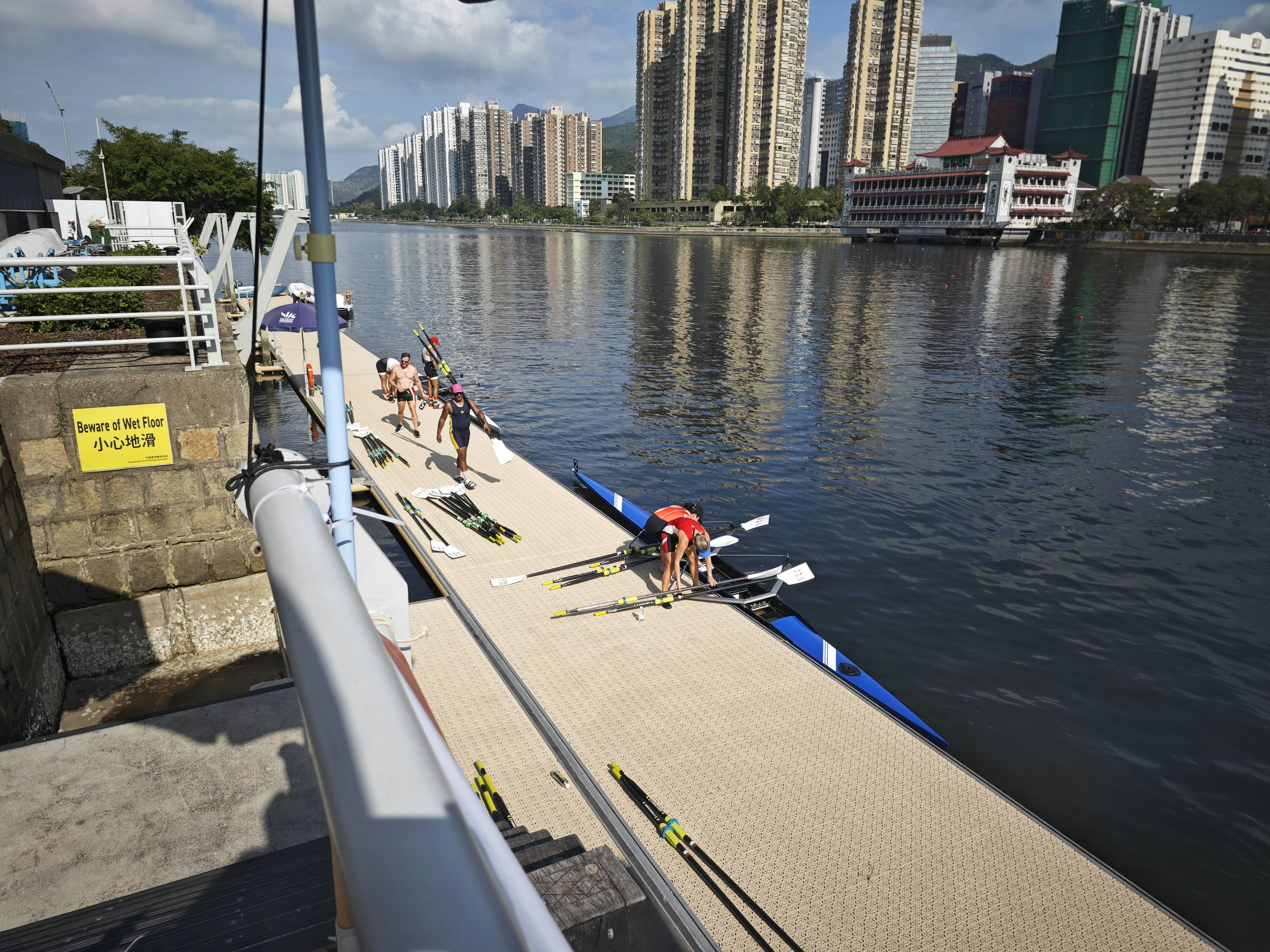 A group of people standing on a dock next to a body of water photo ...