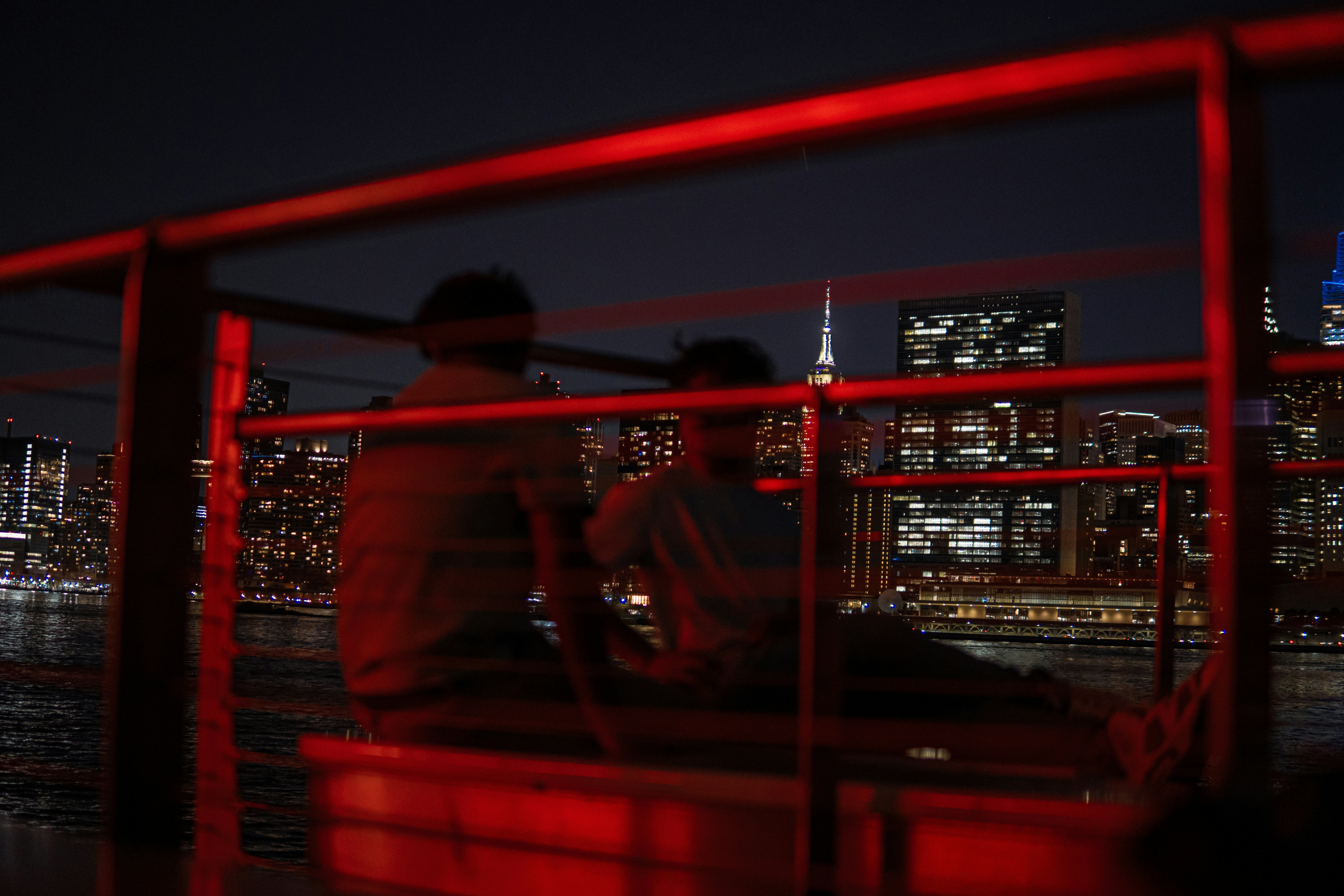 Red Neon Reflections on a Nighttime Riverbank Ride