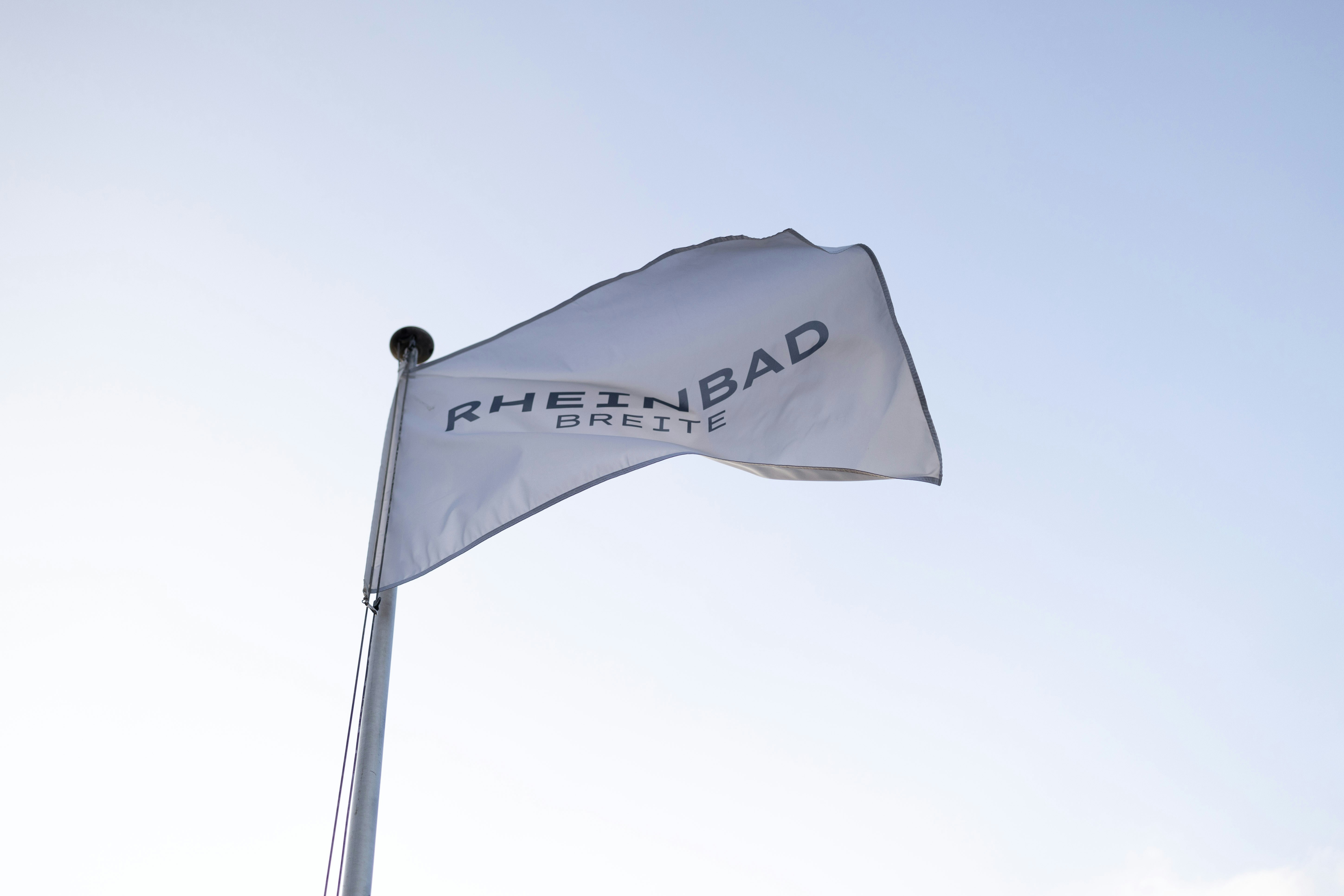 Rheinbad Breite Flag Billowing Under a Quiet Blue Sky
