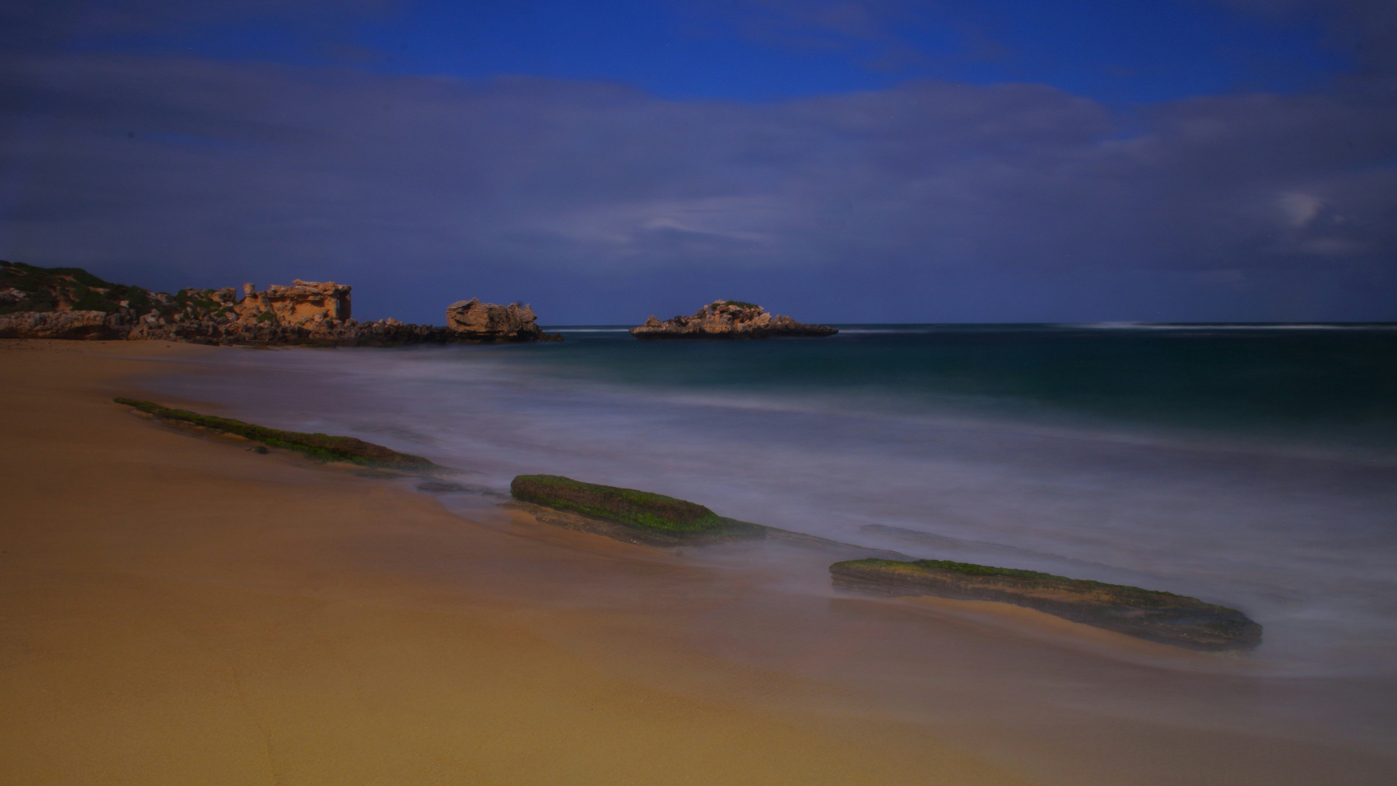 A blurry photo of a beach with rocks in the water photo – Free ...