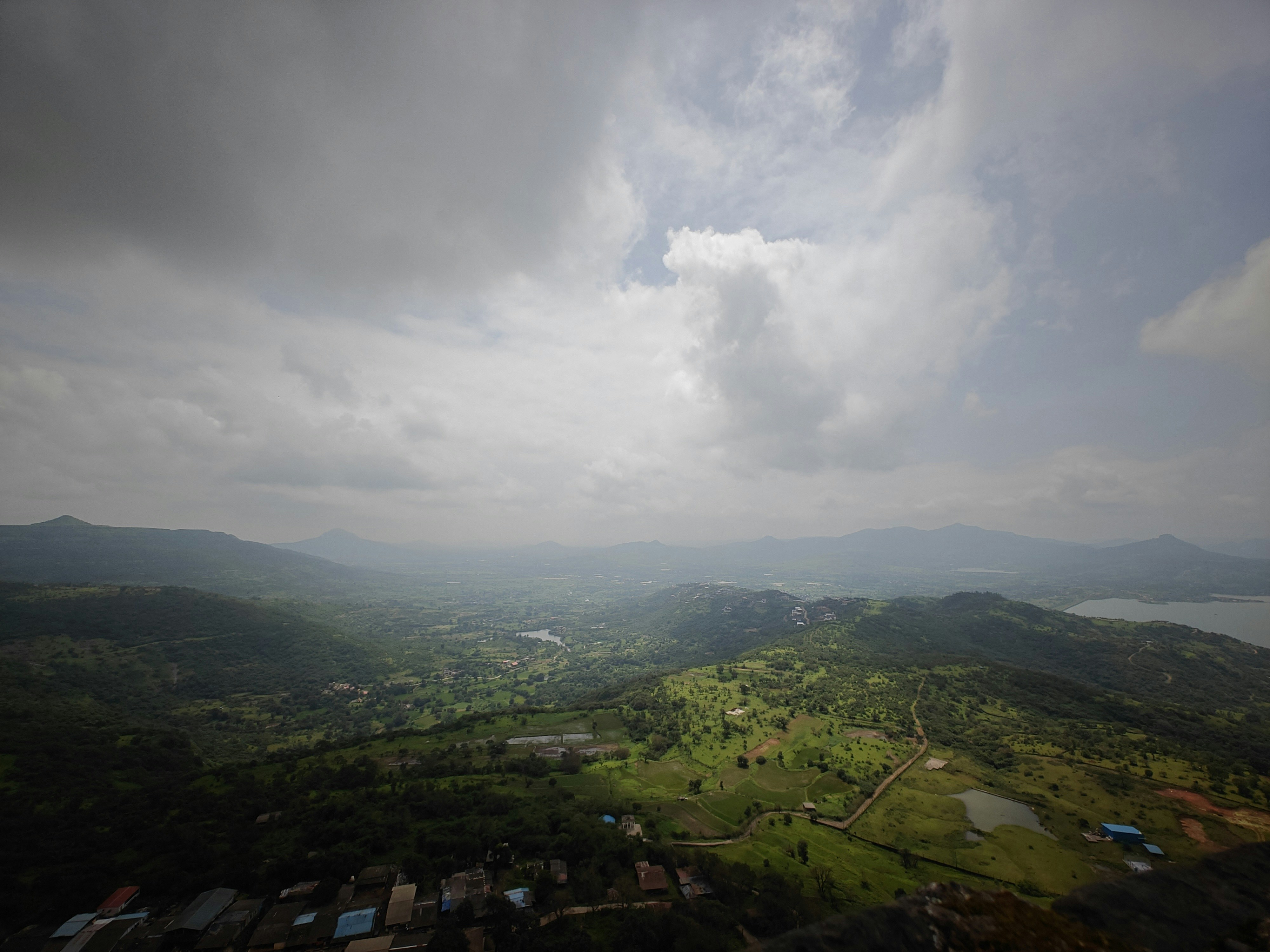 Expansive landscape showcasing lush green valleys and distant mountains under a cloudy sky.