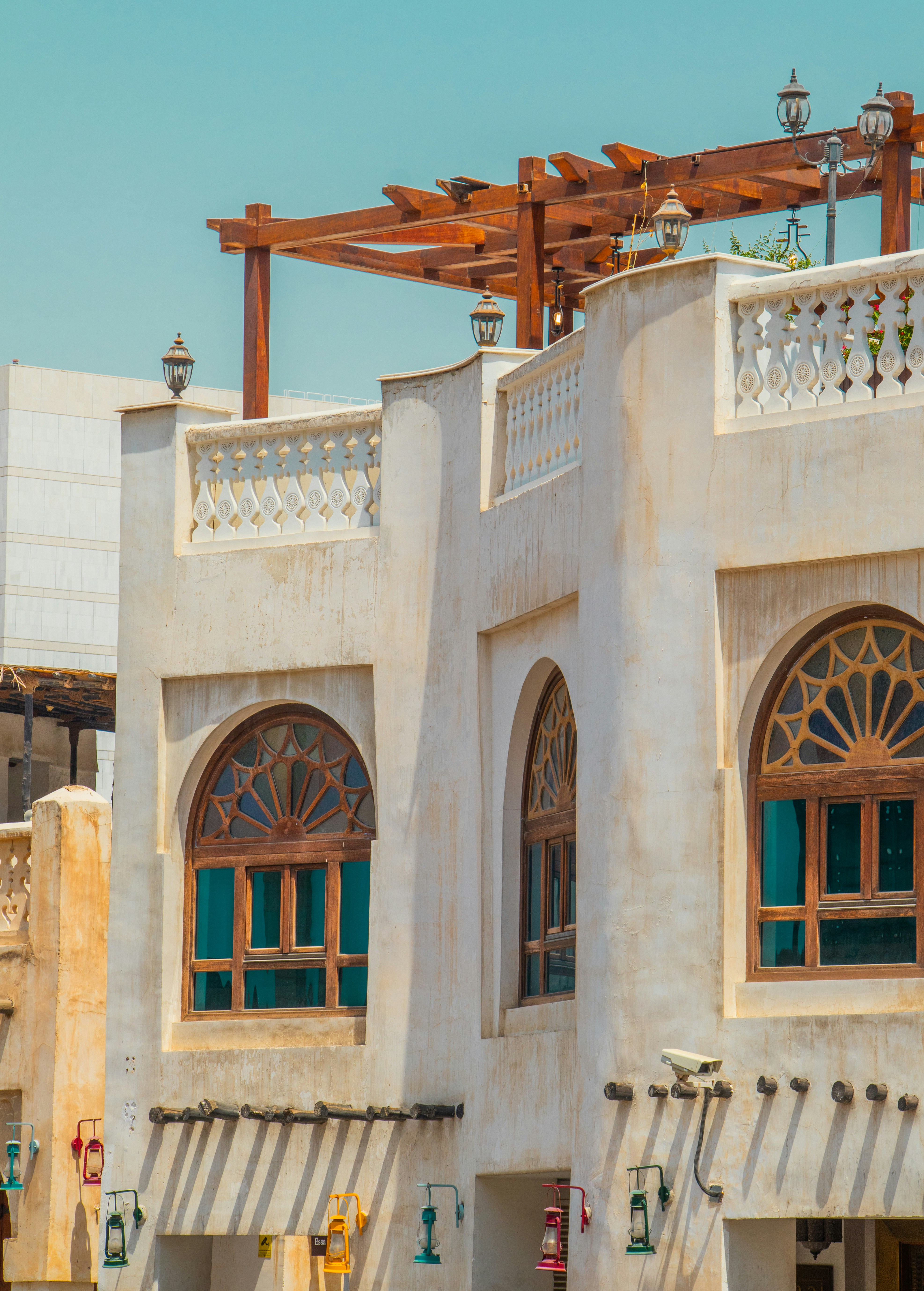 Sunlit Arches and Teal Windows Framing a Mediterranean Courtyard