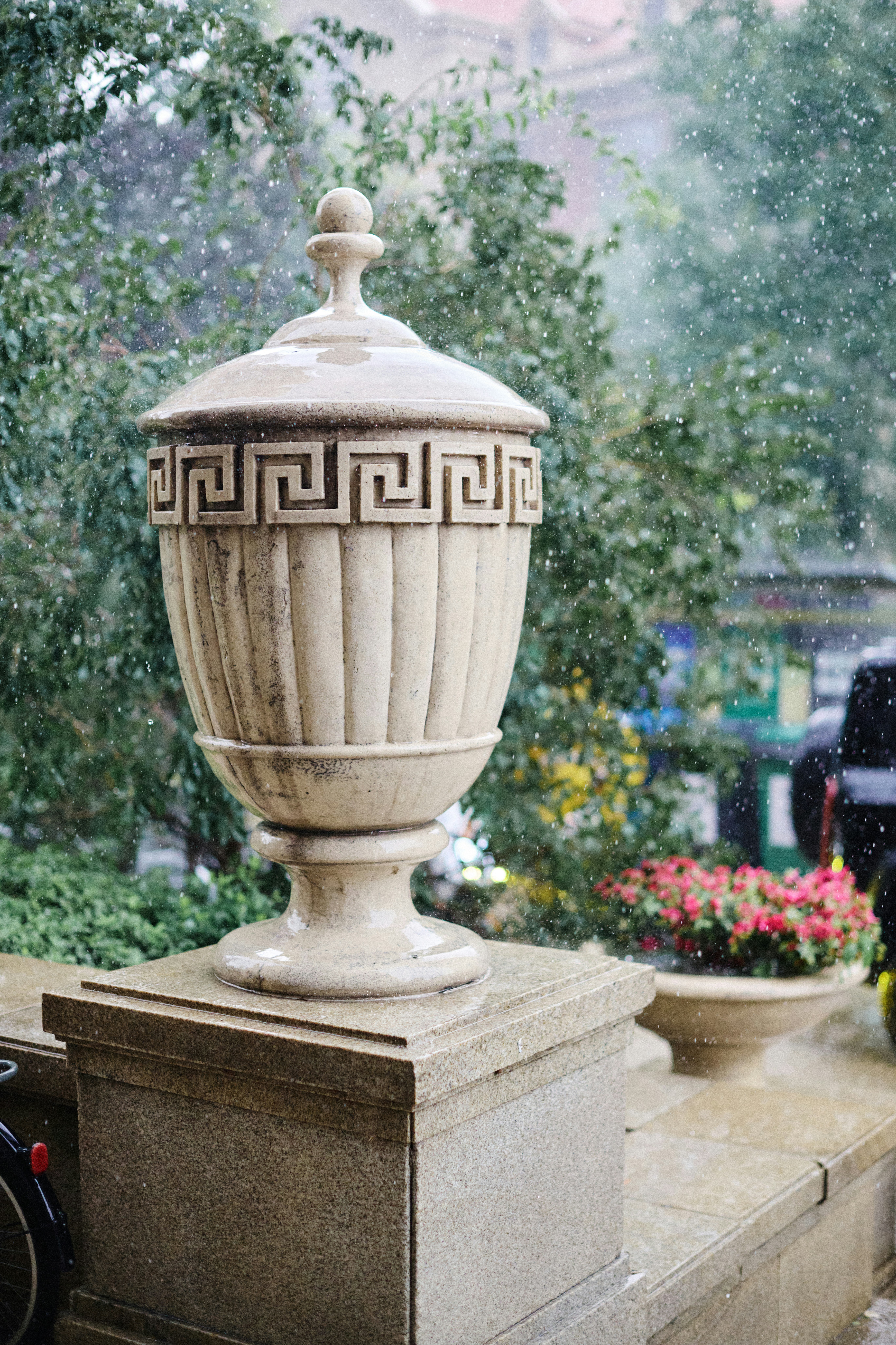 Snow-Kissed Urn: Greek-Key Vessel Standing Guard Over a Quiet City Garden