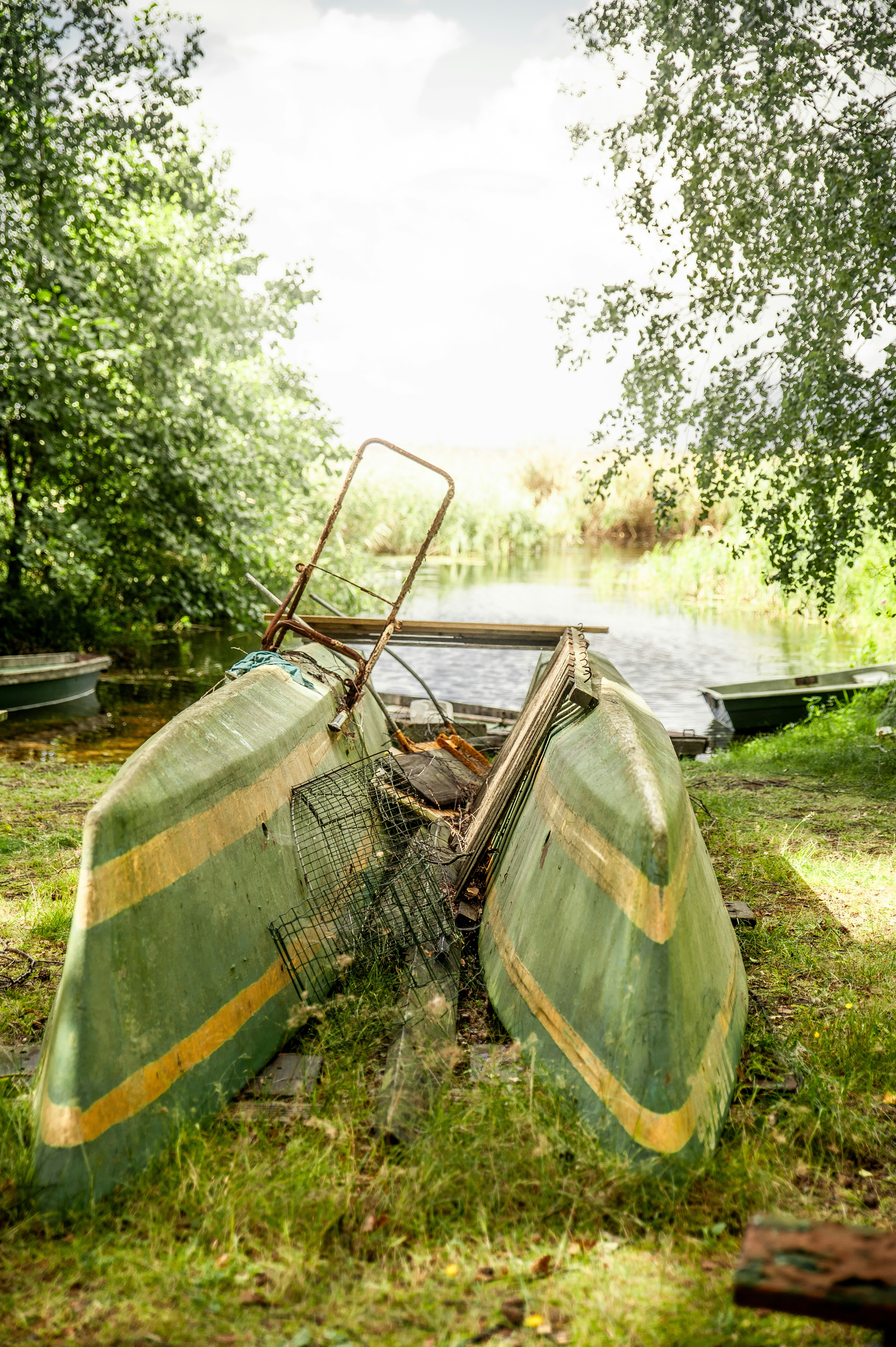 Rusted Frame Between Green Hulls: A Quiet Riverside Moment