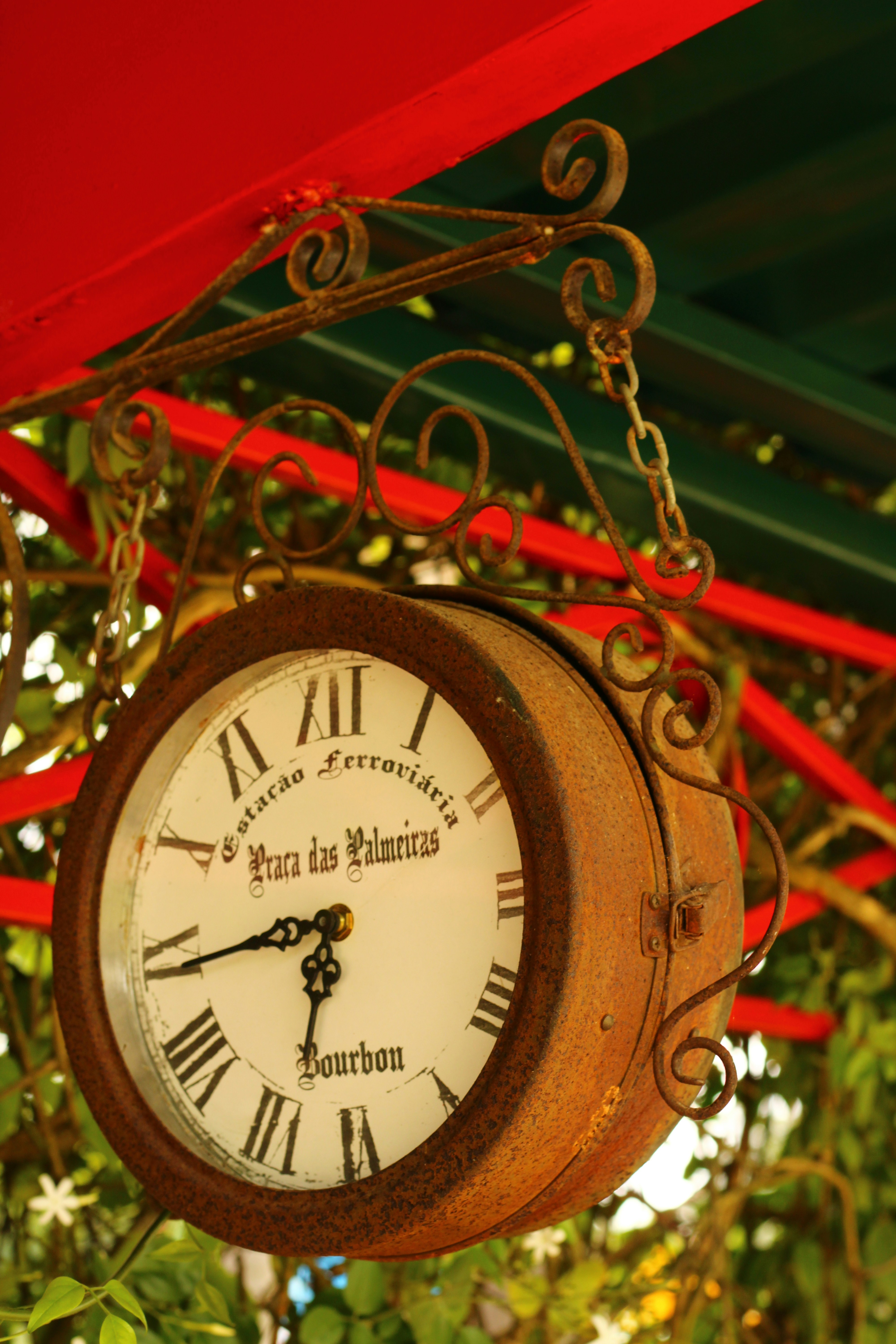Rust, Ribbons and Time: a Hanging Clock Framed by Wrought-Iron Arches