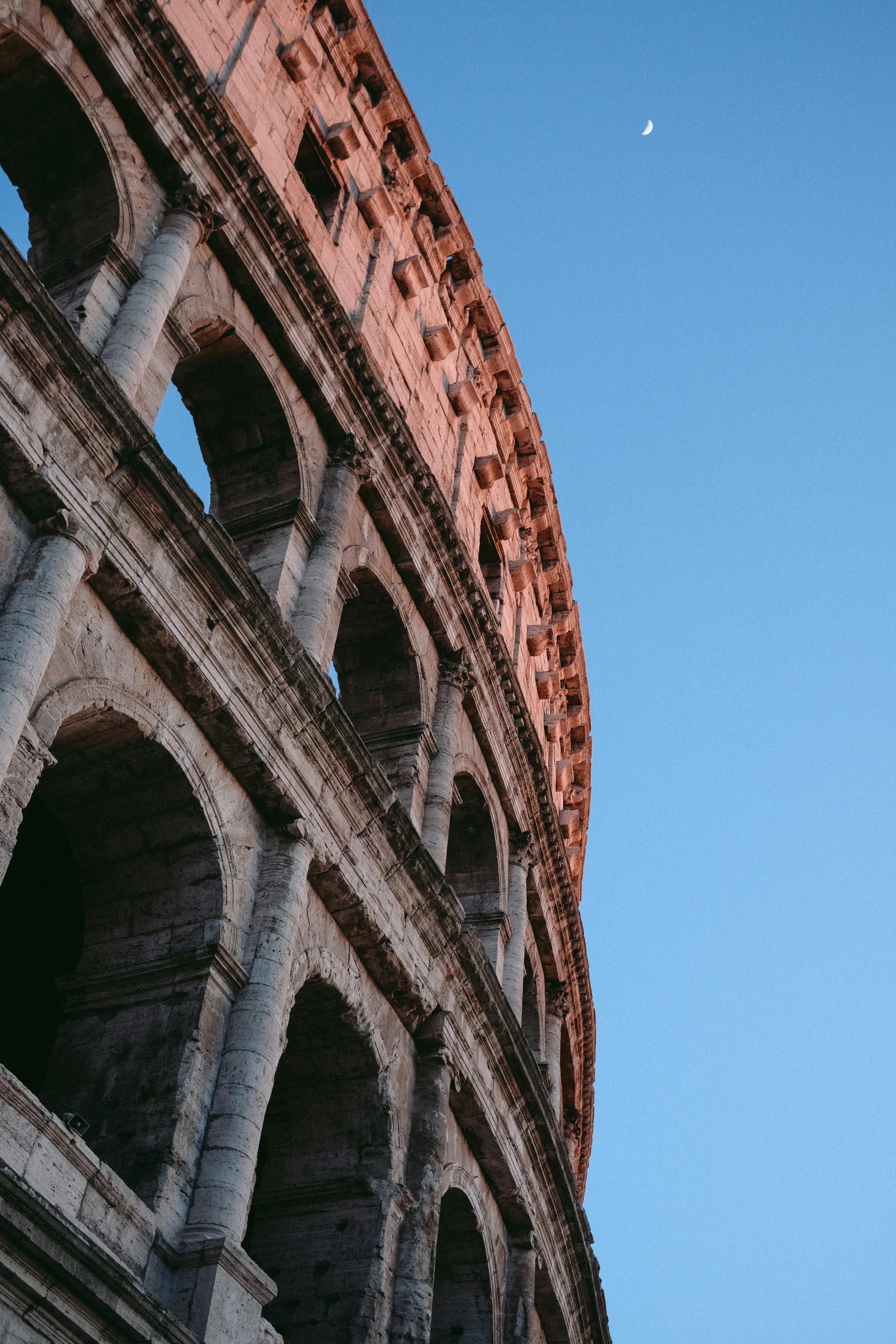 Moonlit Arches: The Colosseum's Curve Against a Clear Blue Sky