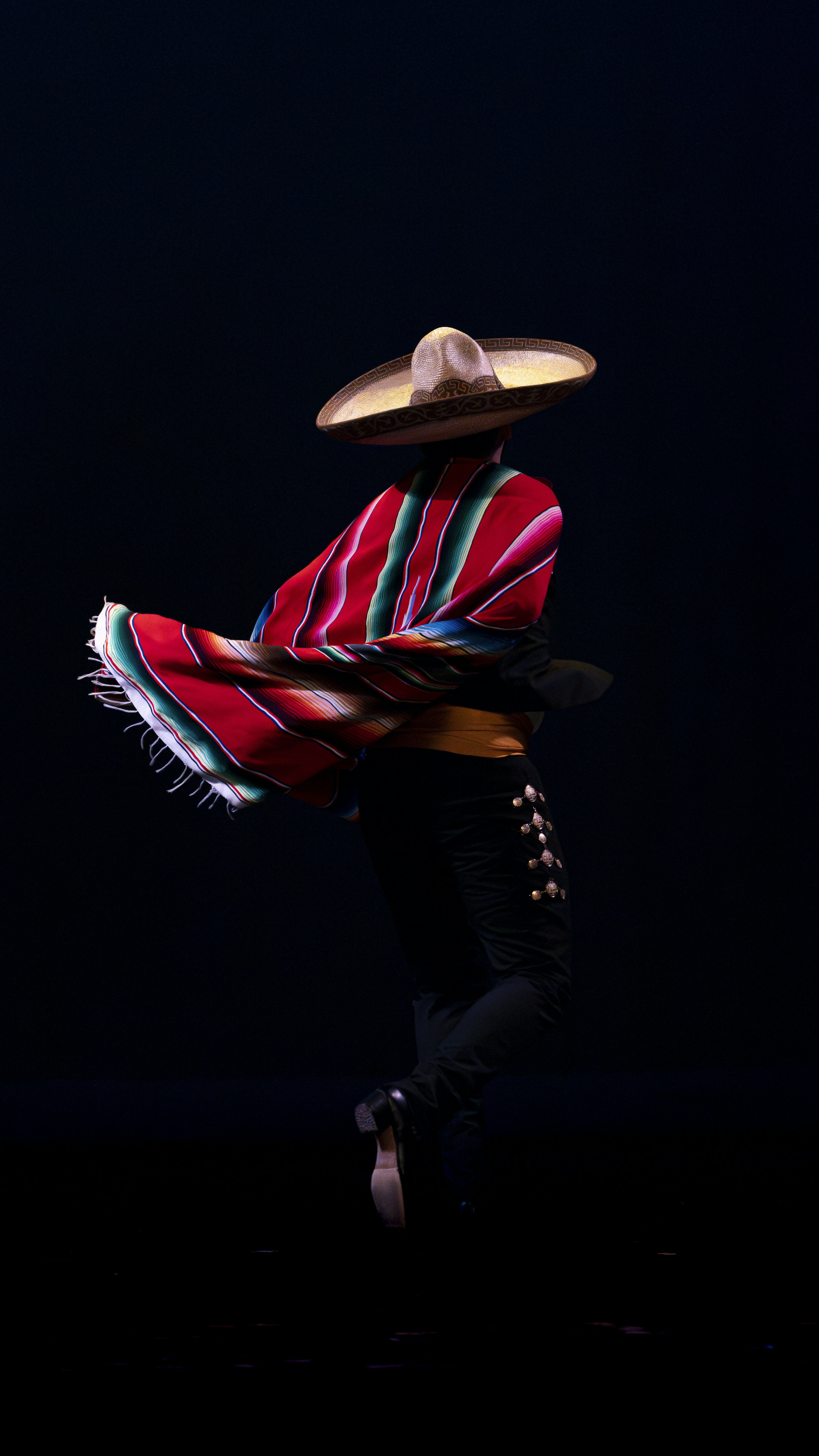 Whirl of Color in Velvet Night: A Dancer Draped in a Striped Poncho