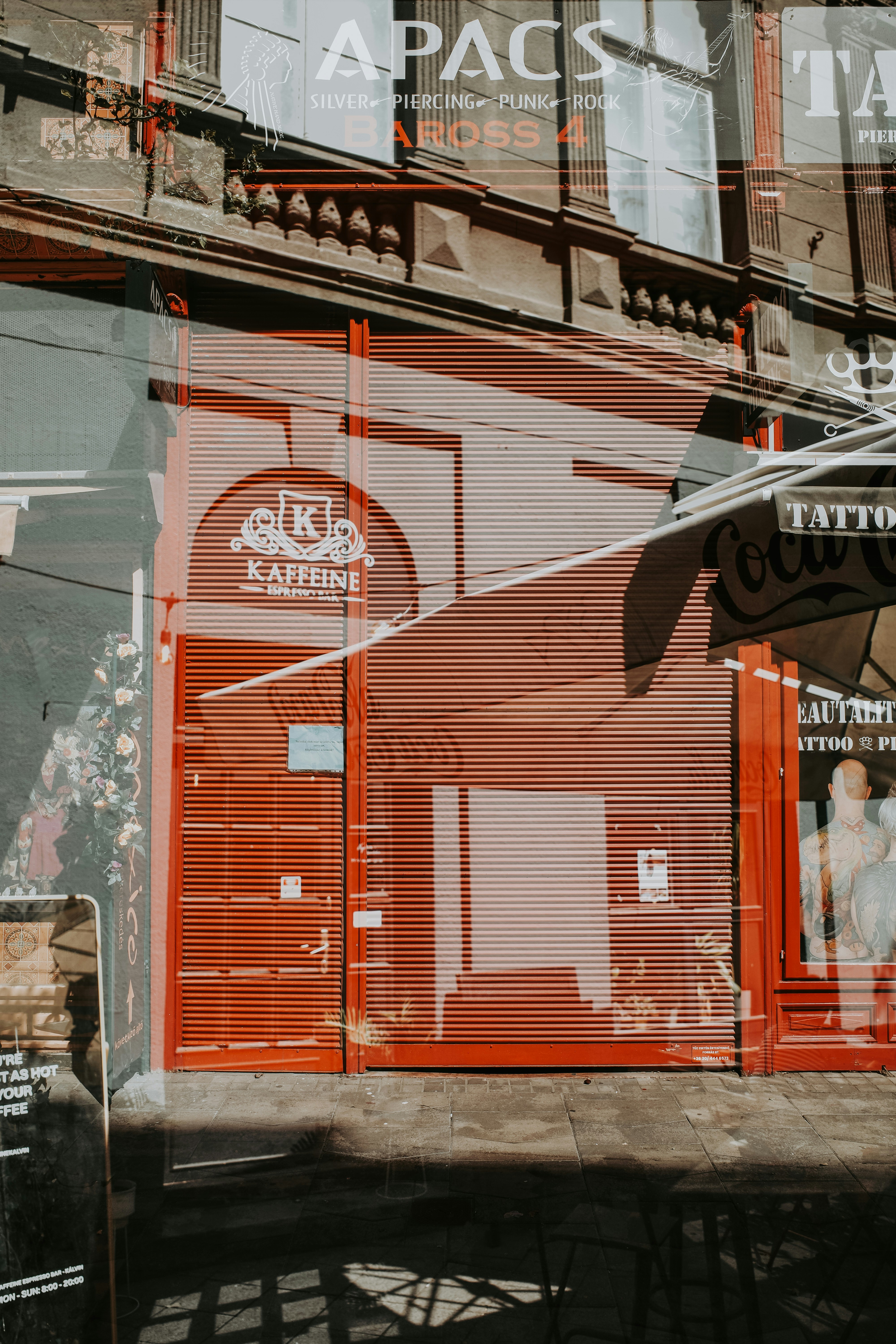 Glass-Overlayed Storefront: Street Scene with Red Doors and Shaded Signage