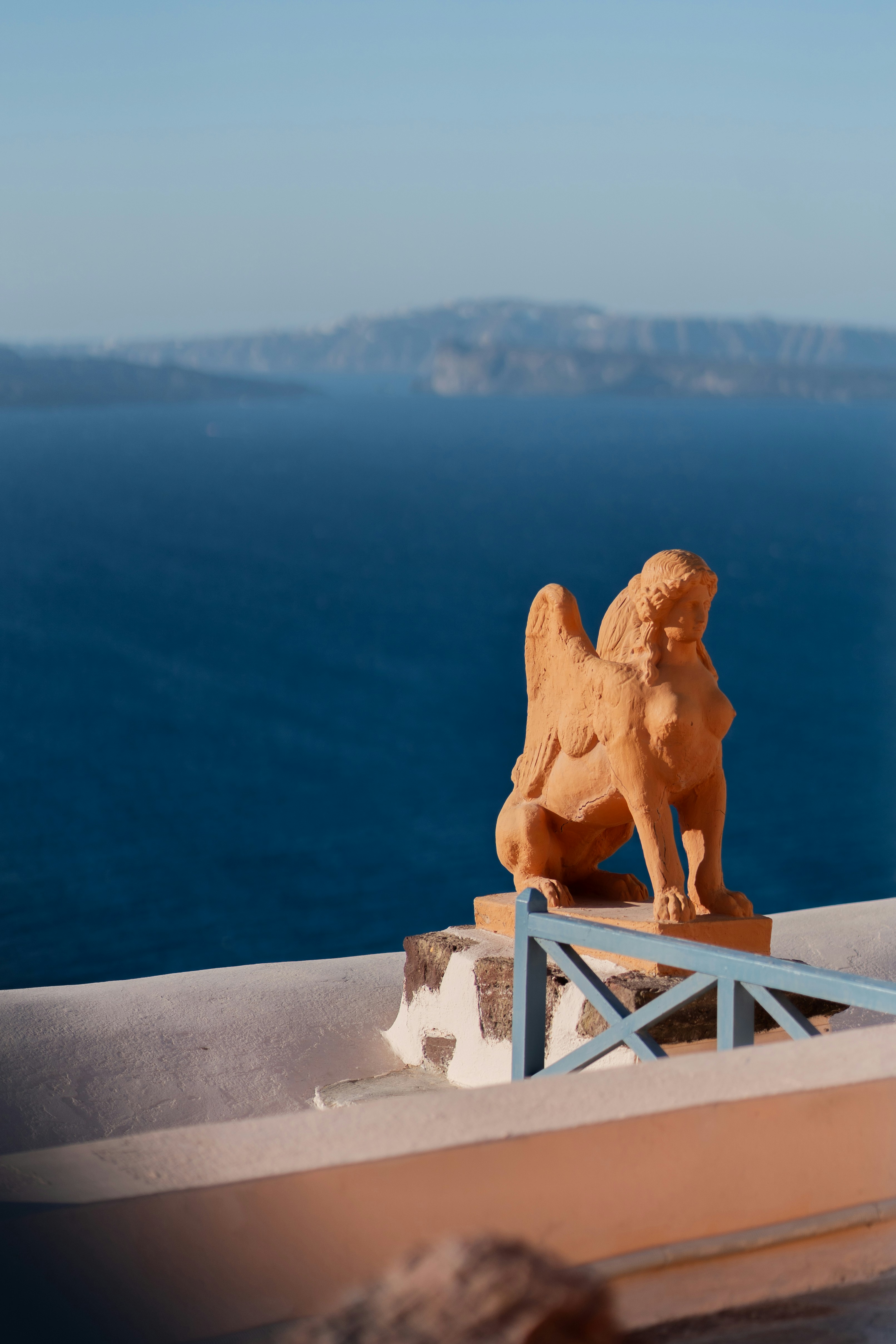 Terracotta Guardian on a Santorini Terrace Beneath an Expansive Aegean Blue