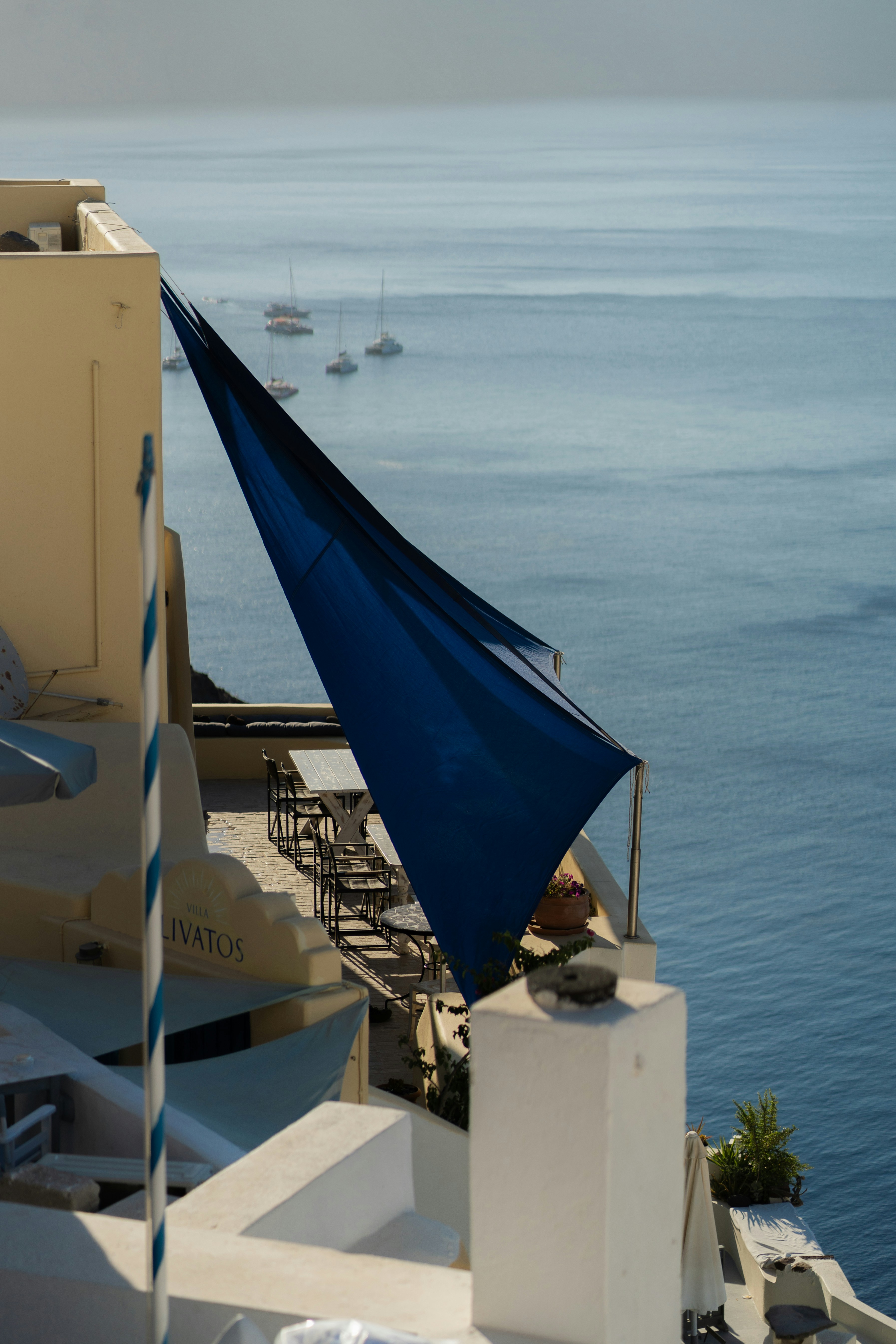 Blue Sailshade Over White Terrace with Sea View