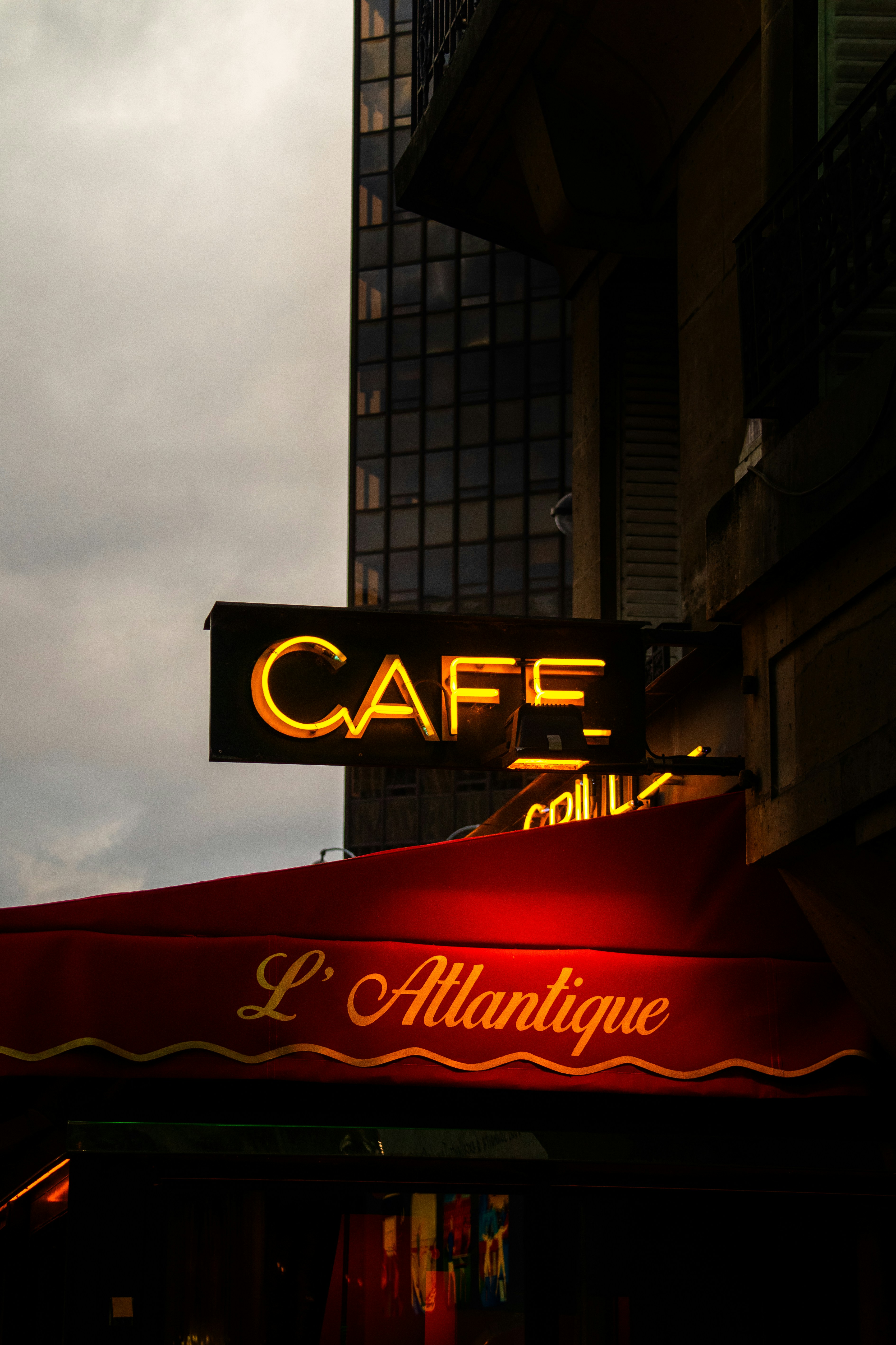 Neon CAFE Sign Casting Warm Glow Over a Parisian Red Awning at Dusk
