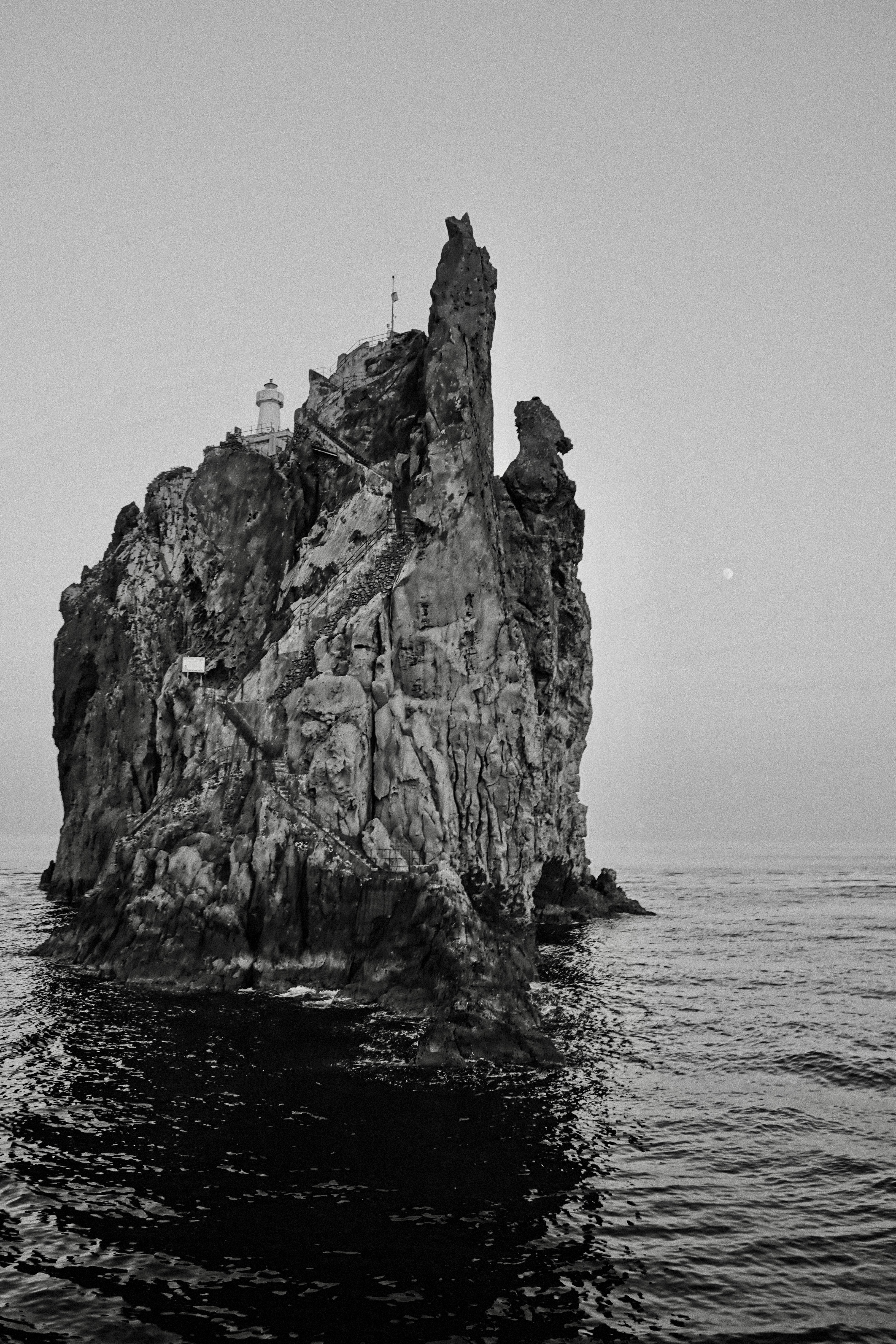 Lone Sea Stack: A Mono Horizon Rising from Calm Waters