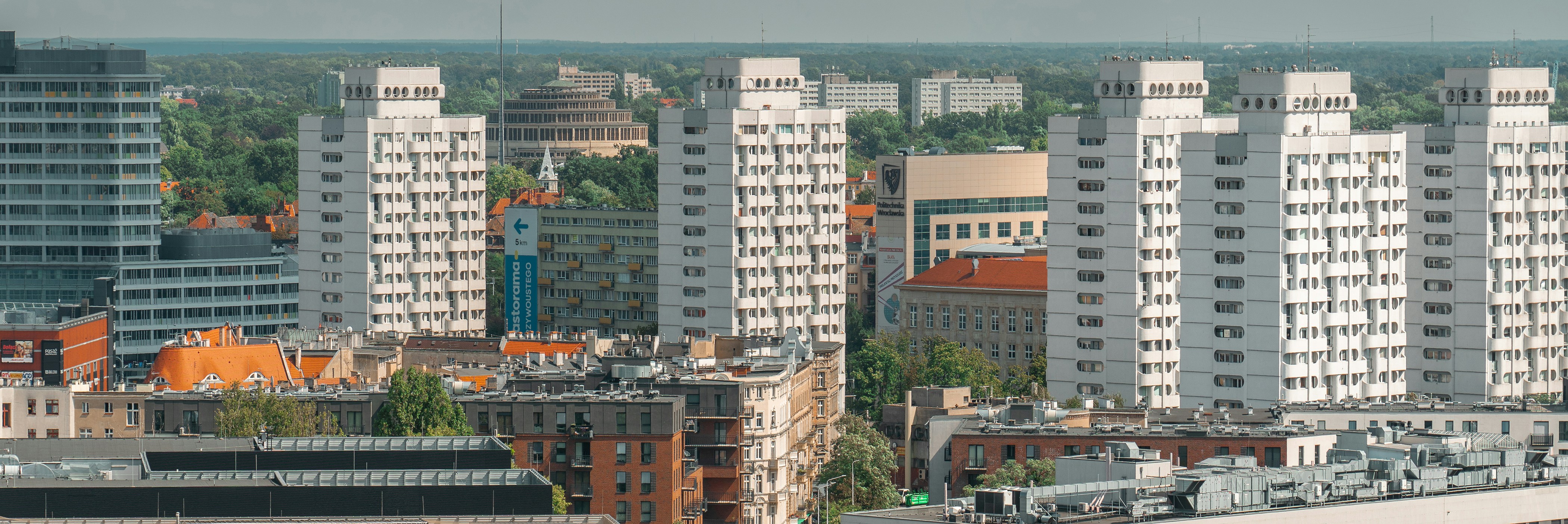 High-rise residential buildings stand amidst a sprawling cityscape under a clear sky.