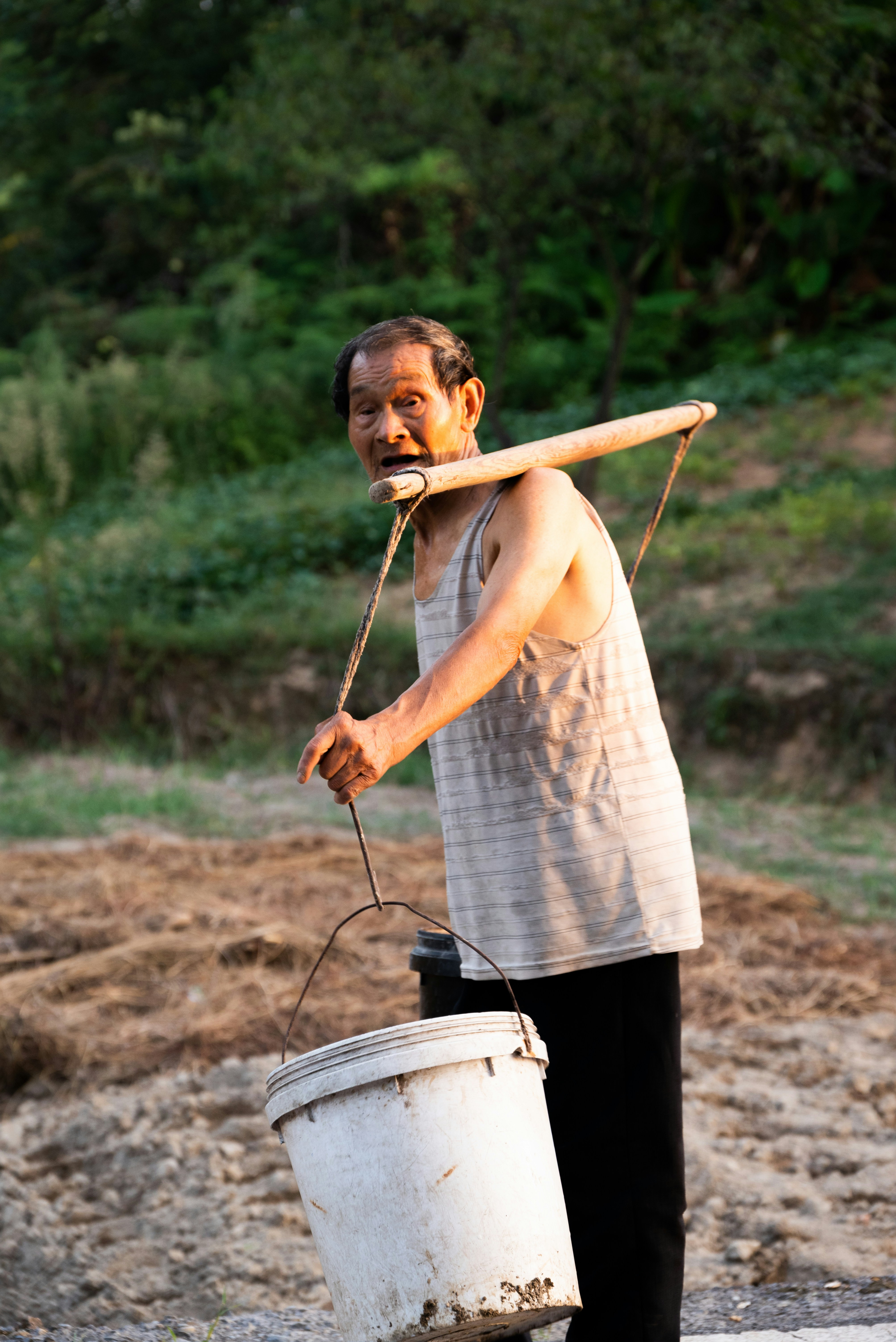 A man carrying a bucket and a stick photo – Free Sunshine Image on Unsplash