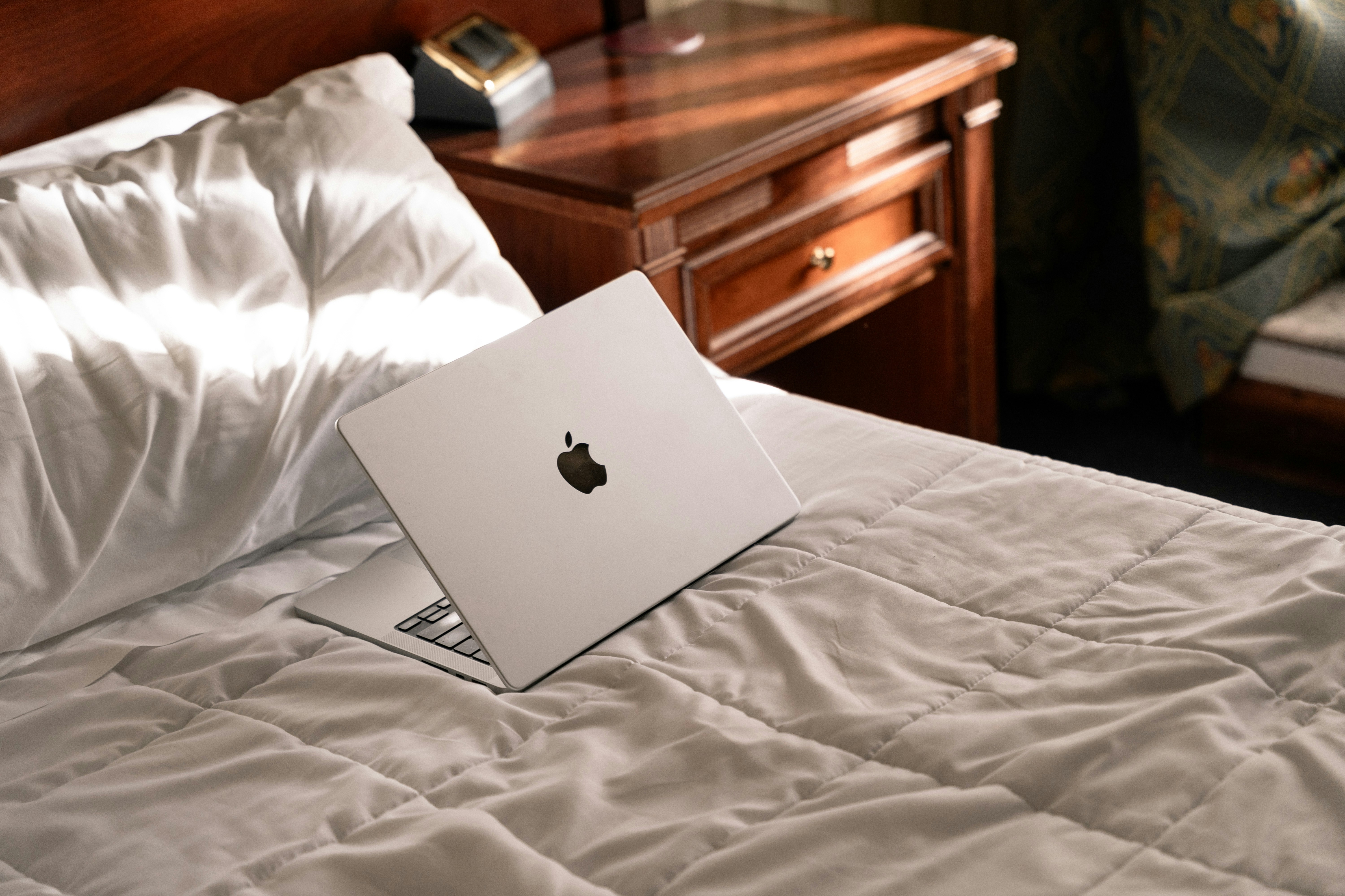 An apple laptop sitting on top of a bed photo – Free Apple Image on ...