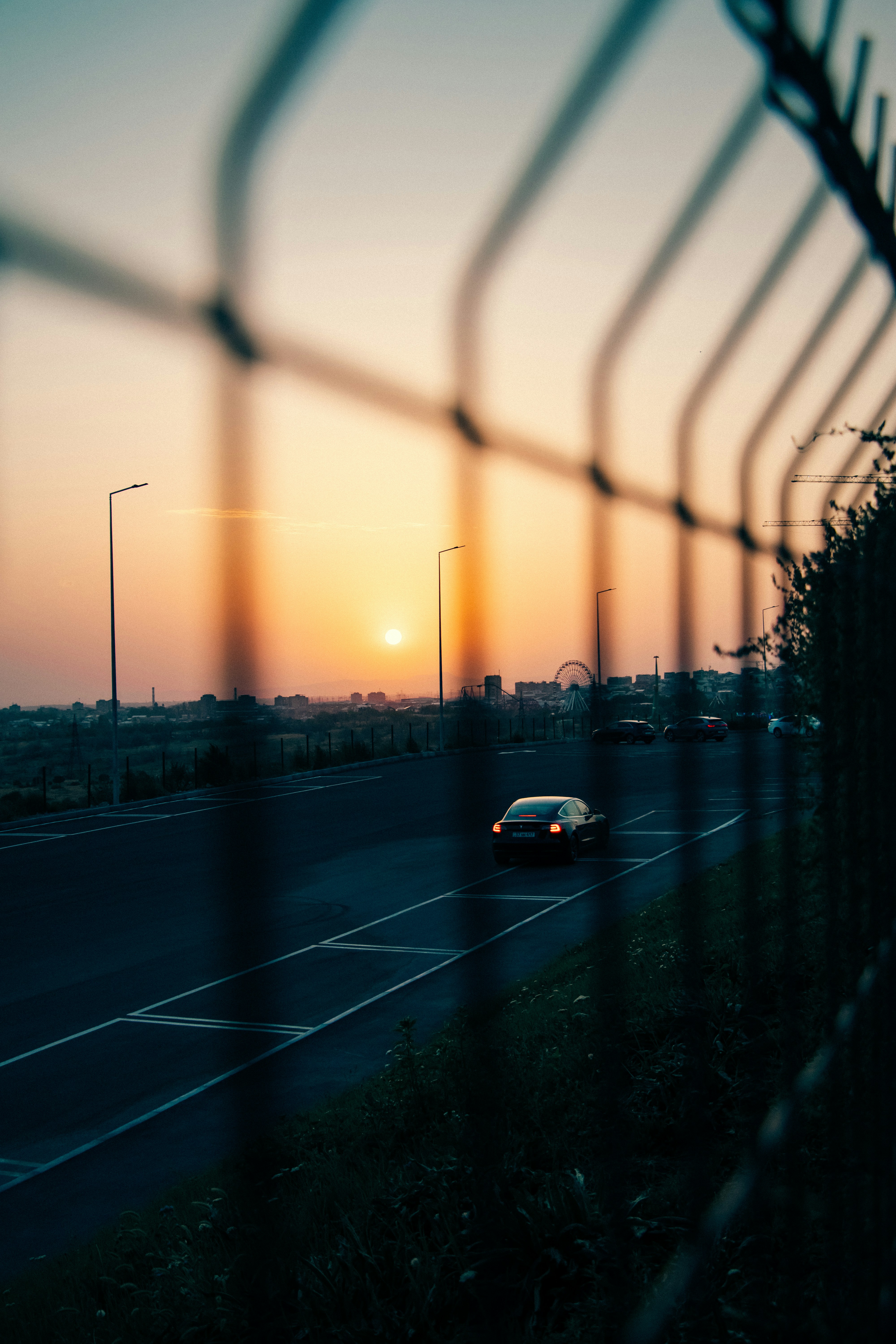 Horizon Framed by Chain-Link: Sunset Drive on a Quiet Highway