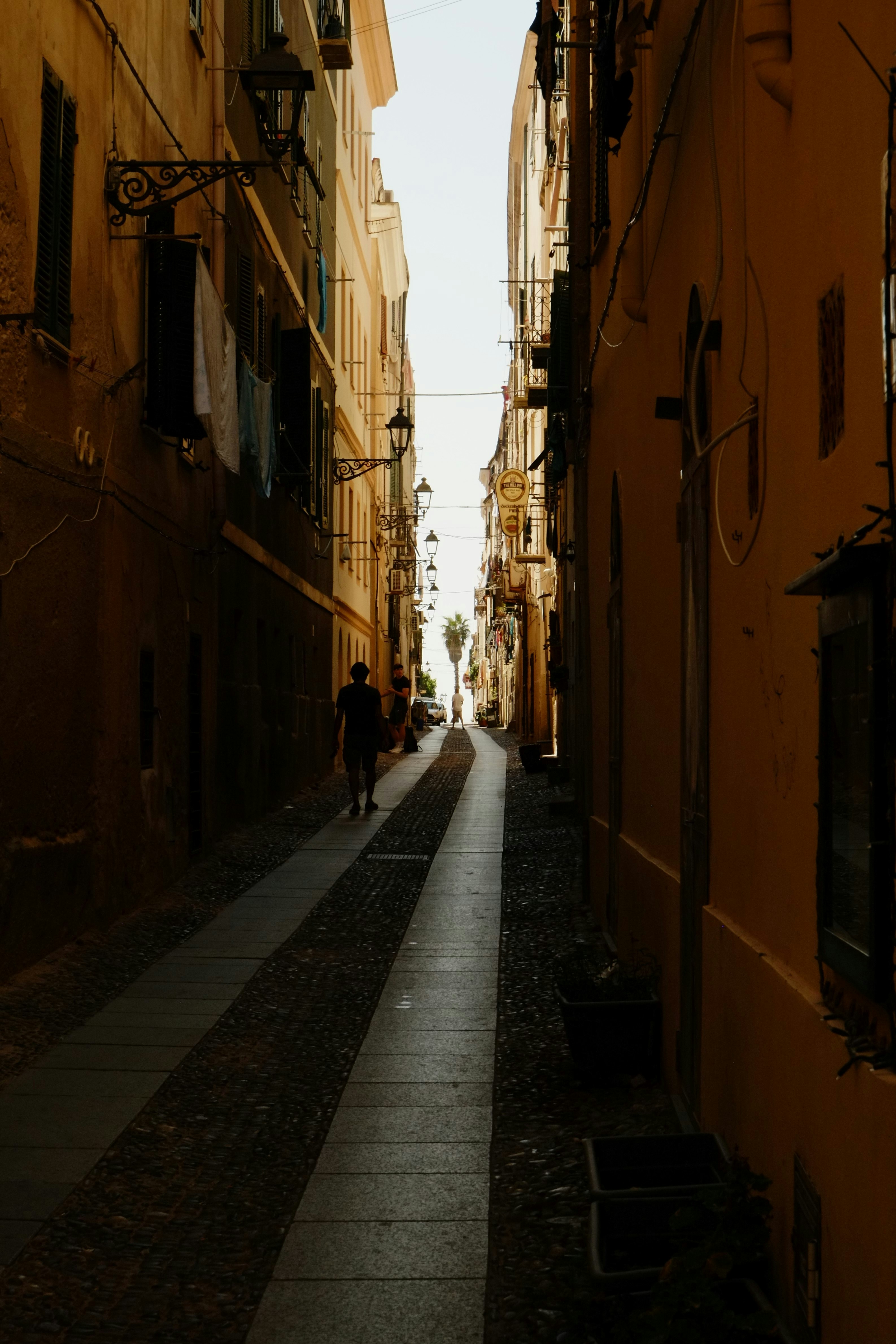 A narrow alley way with people walking down it photo – Free Alghero ...