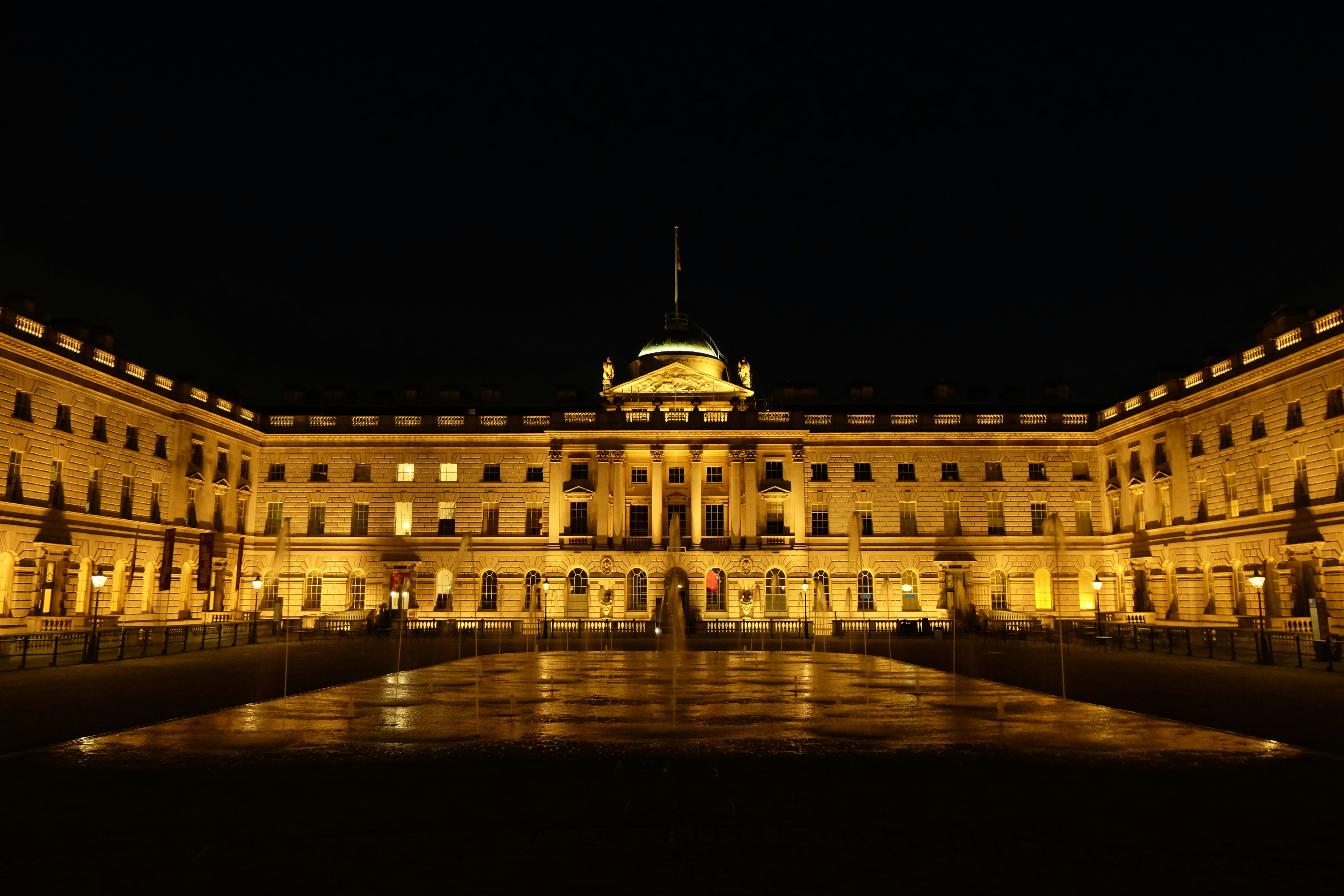 Illuminated historic building with symmetrical architecture glowing against a dark night sky.