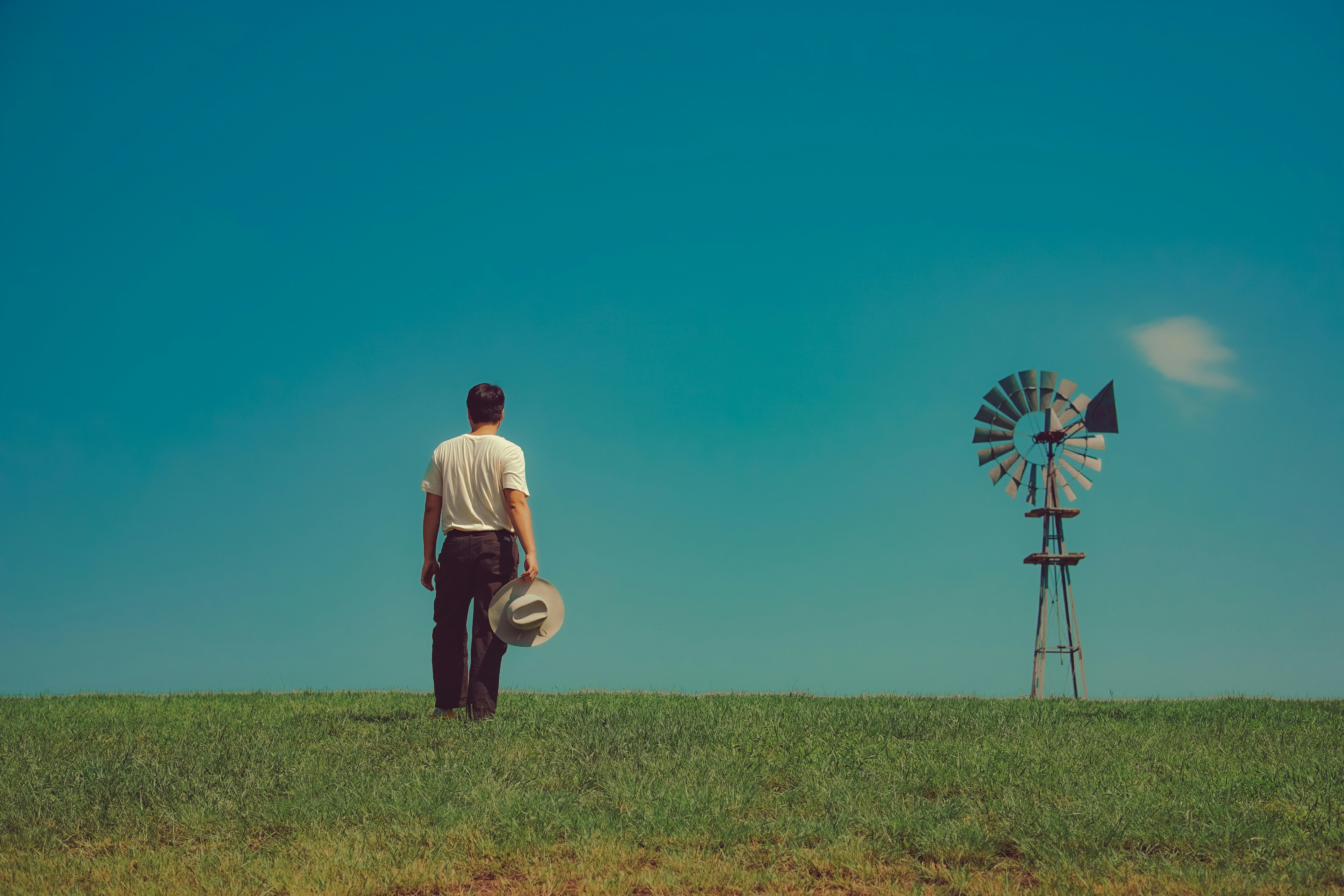 man out in a field near a windmill