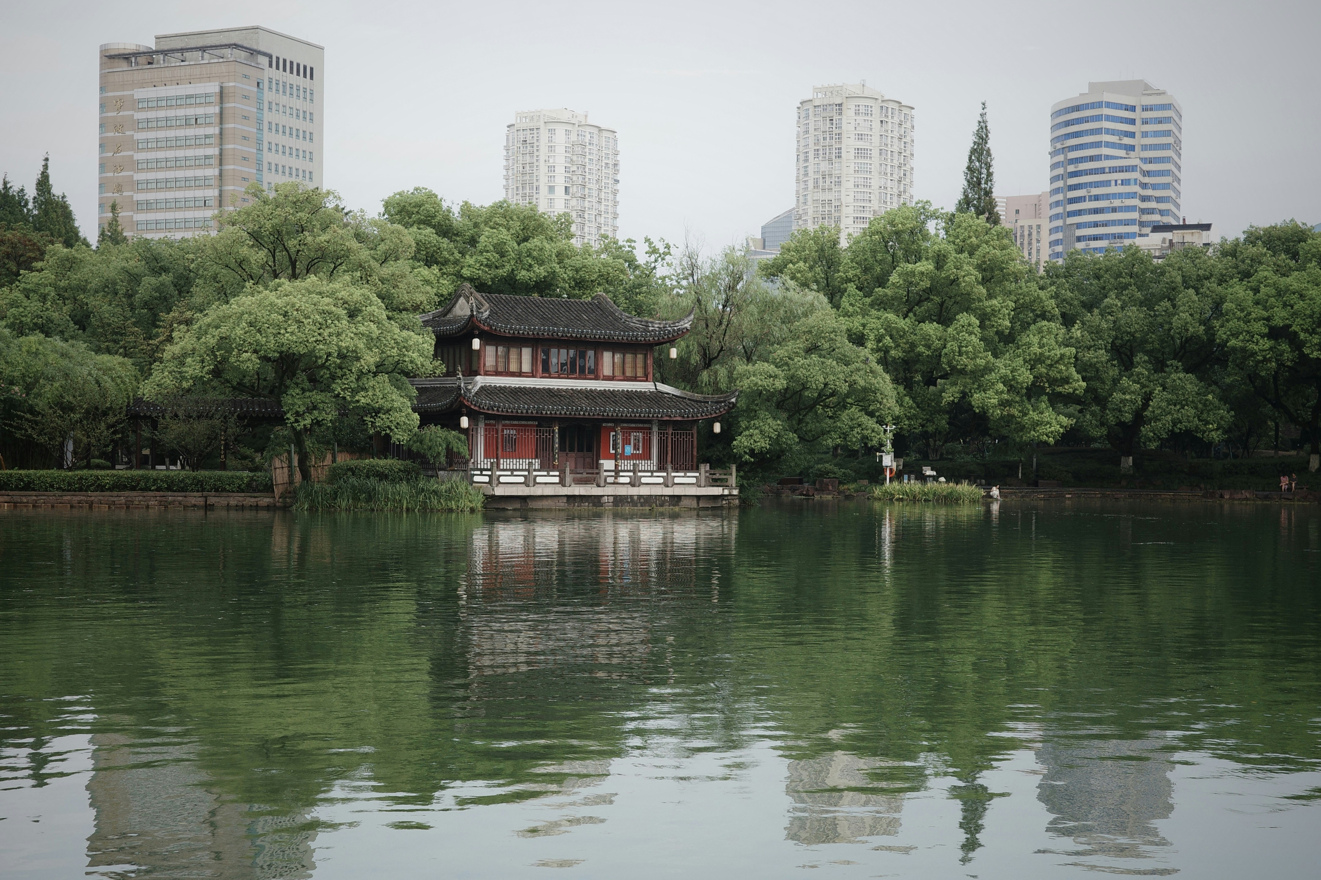 A building sitting on top of a lake next to tall buildings