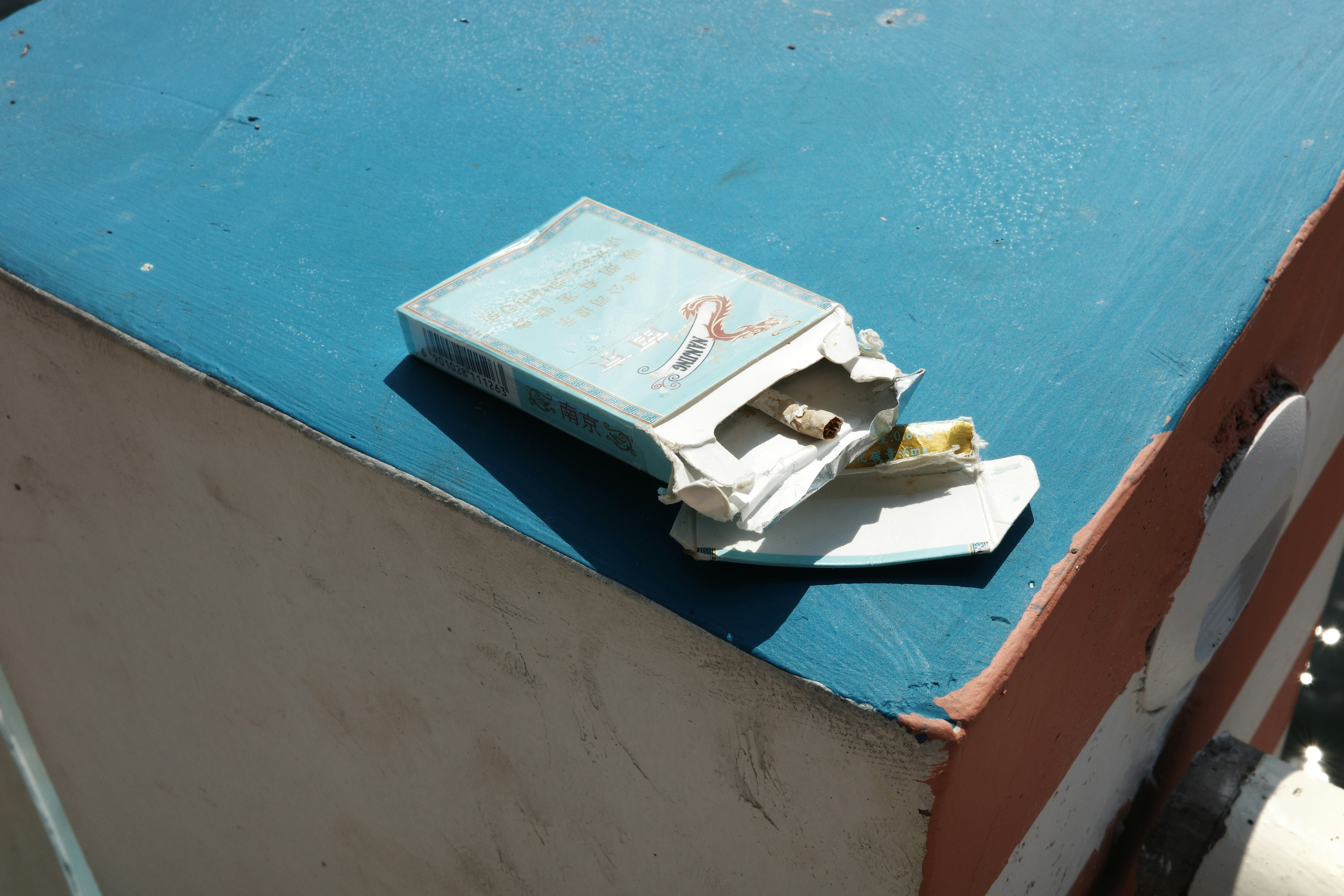 Blue Countertop Still Life: A Crumpled Pack Under Sunlight