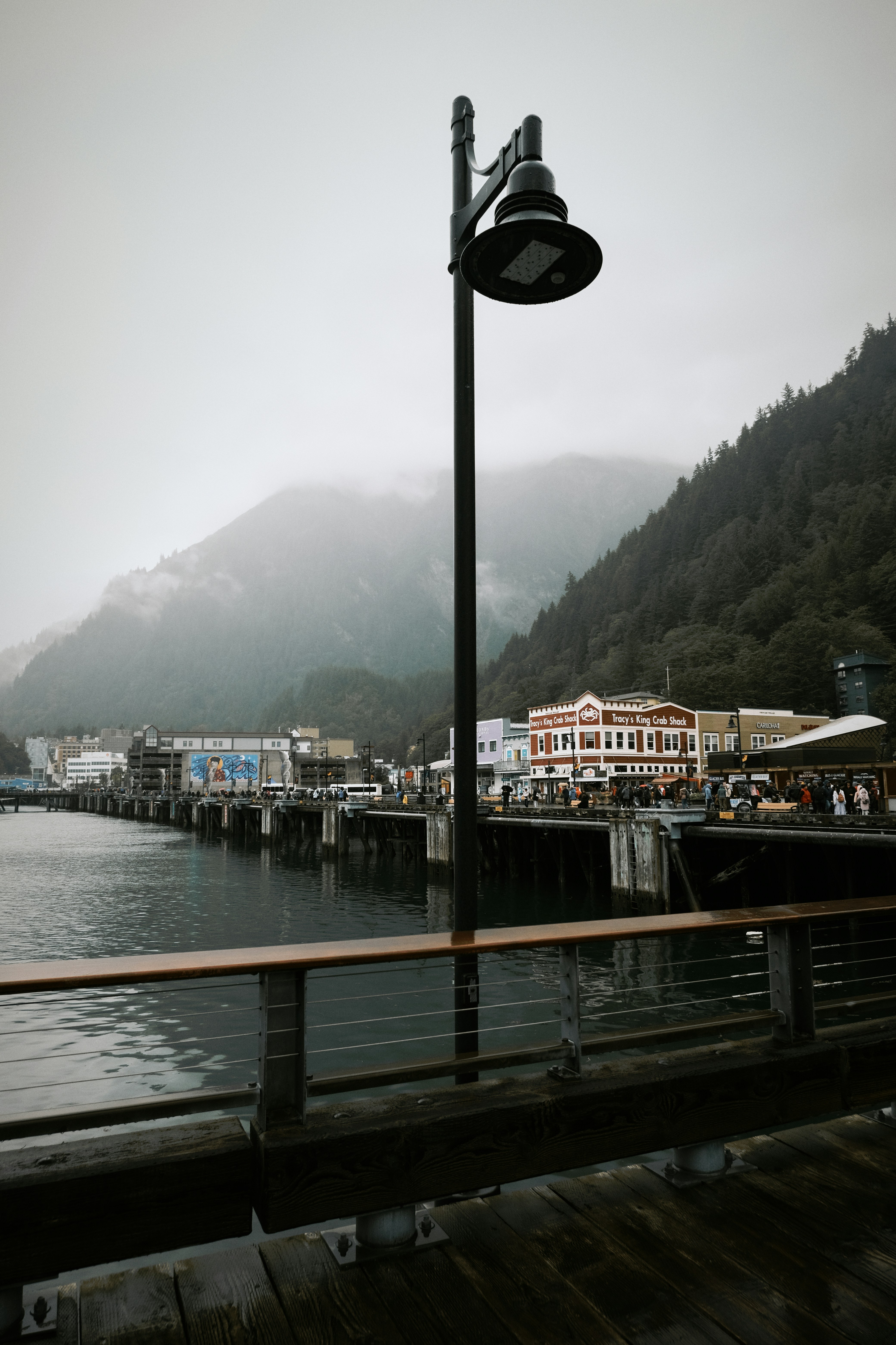 Lamppost in the Mist: Harbor Pier Under Fog-Shrouded Mountains