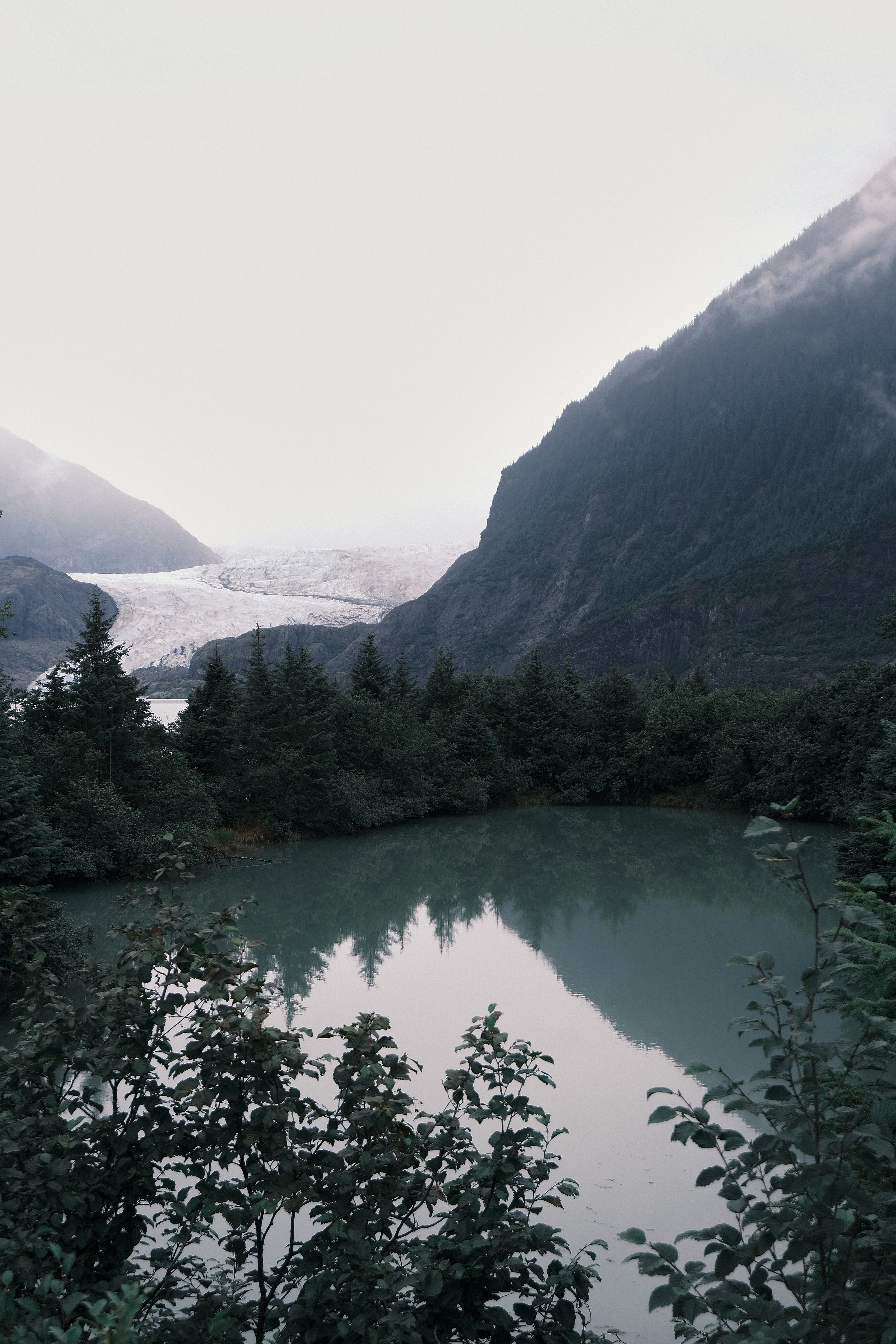 Glacial Valley Confluence: A Serene Lake Between Steep Slopes