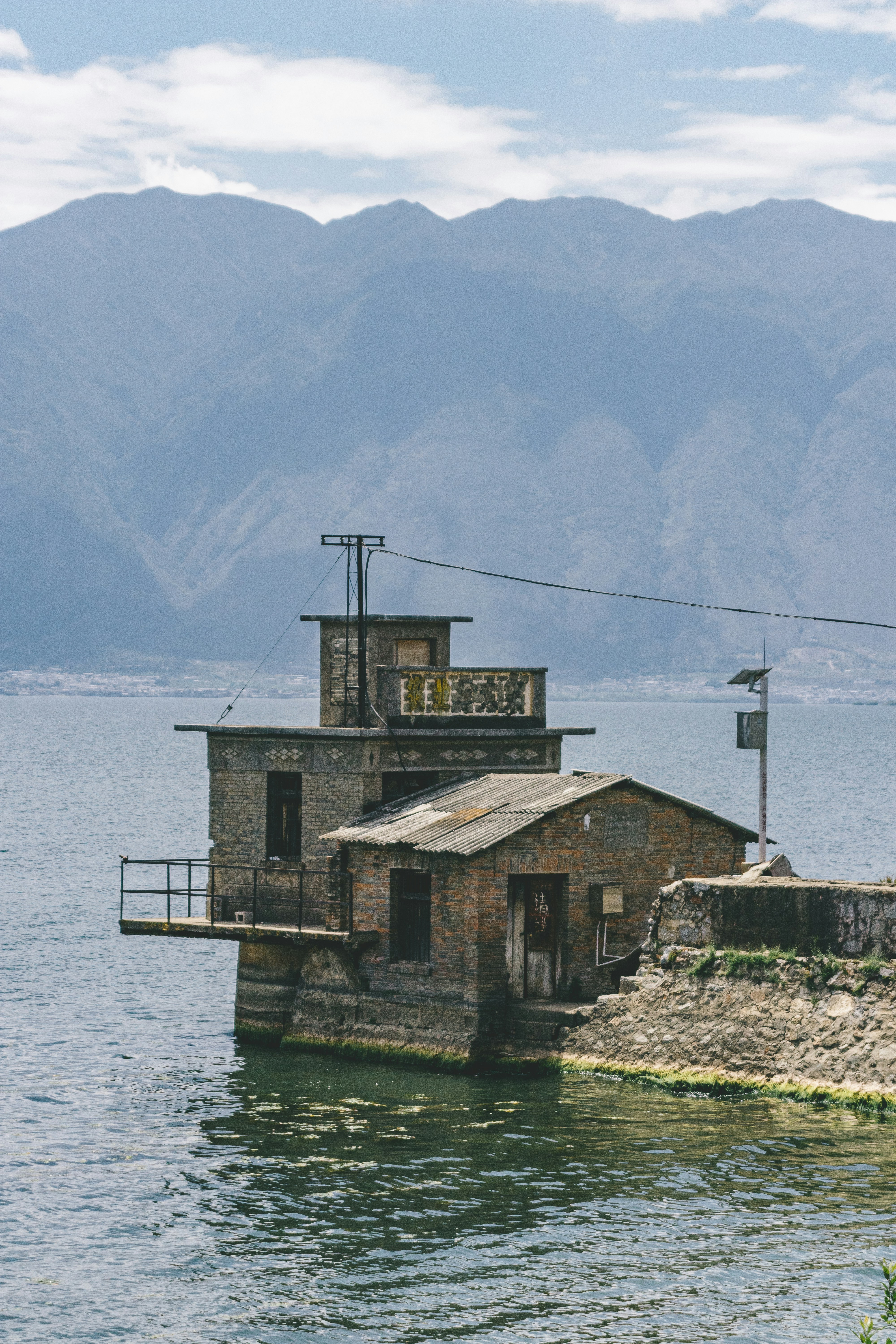 Rustic boathouse on a calm lake, framed by distant mountains