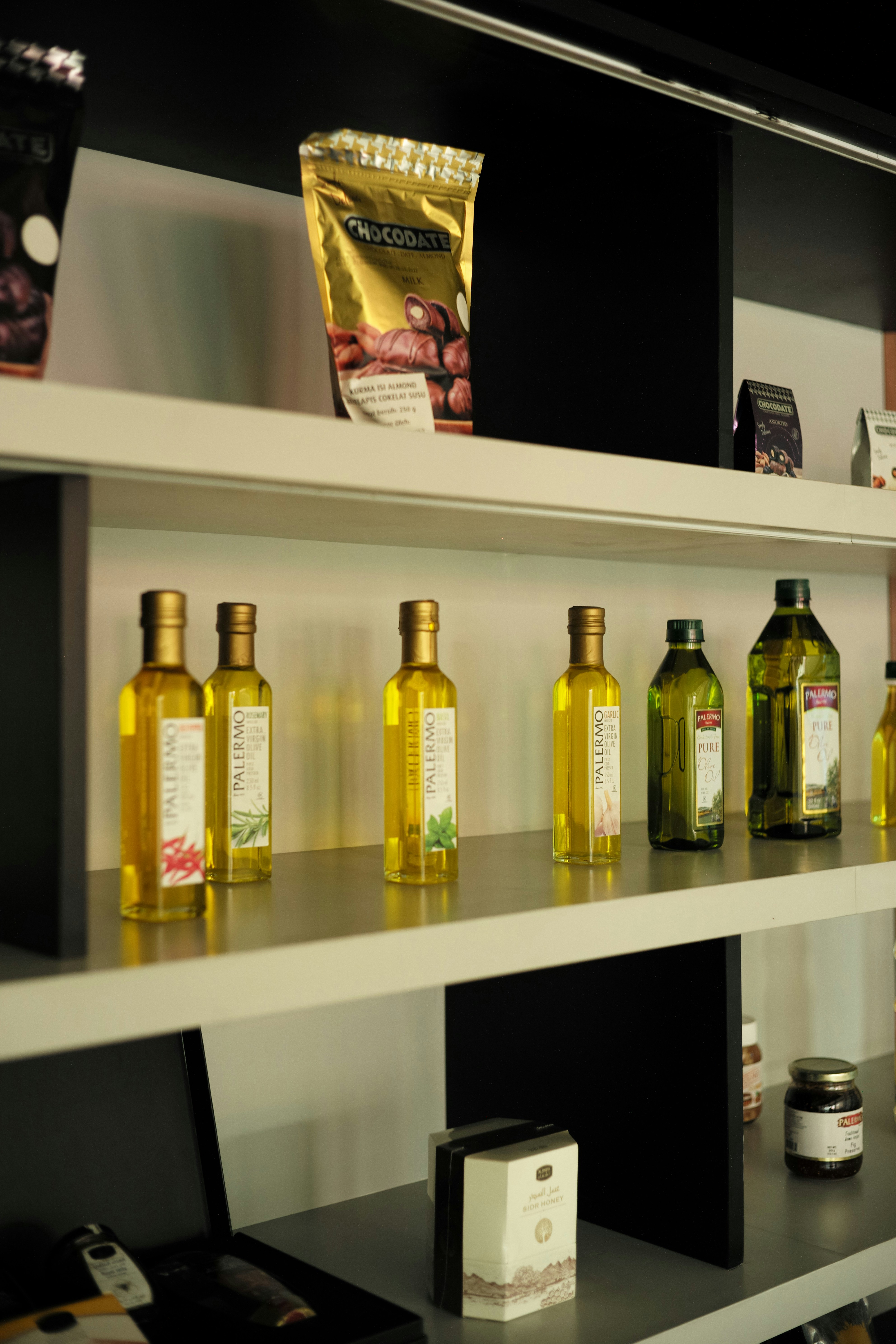 Shelf of Gold: Olive Oil Bottles and Premium Chocolates on Display