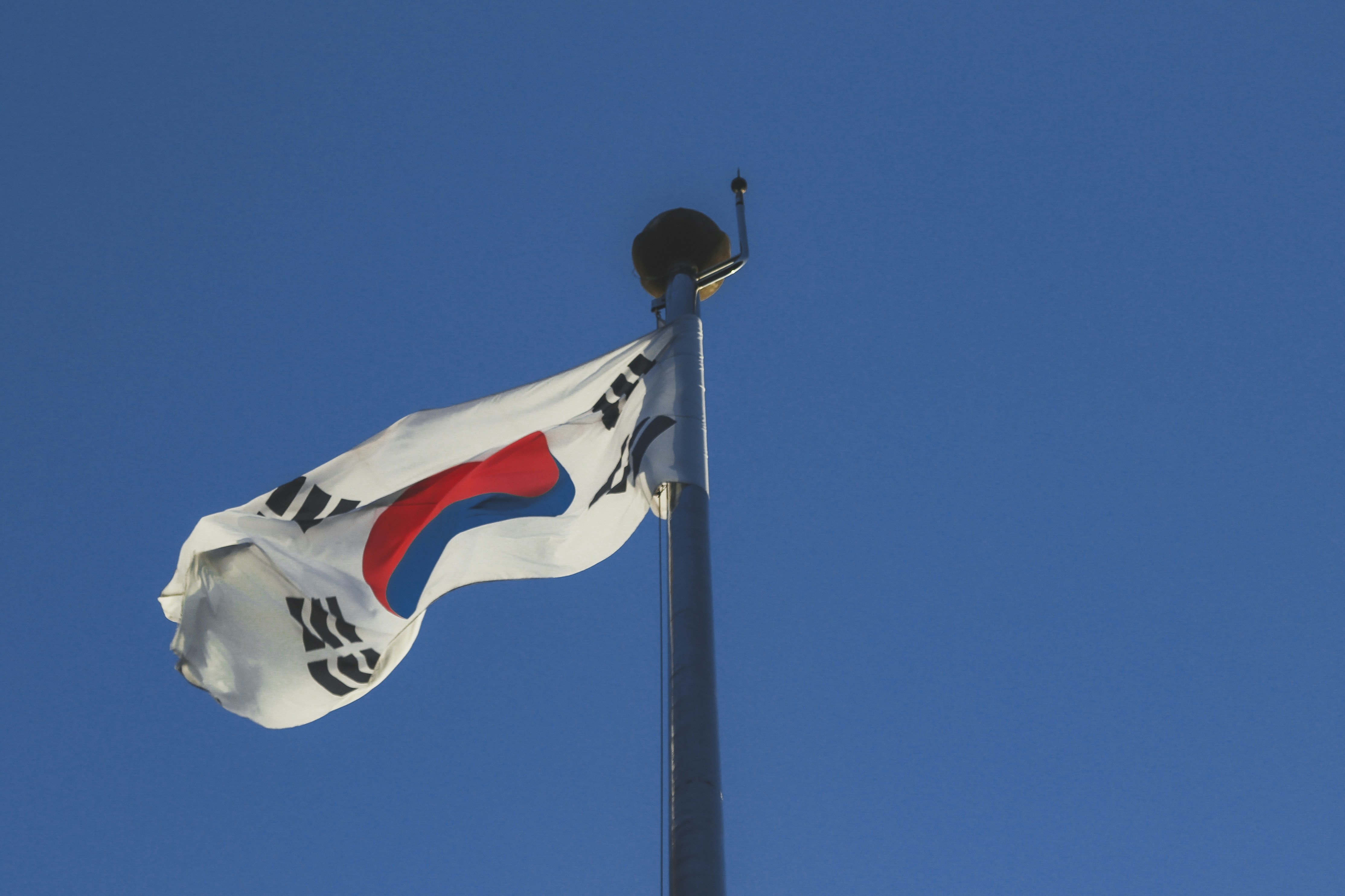 Korean Taegeuk Unfurls at the Flagpole Under a Clear Blue Sky
