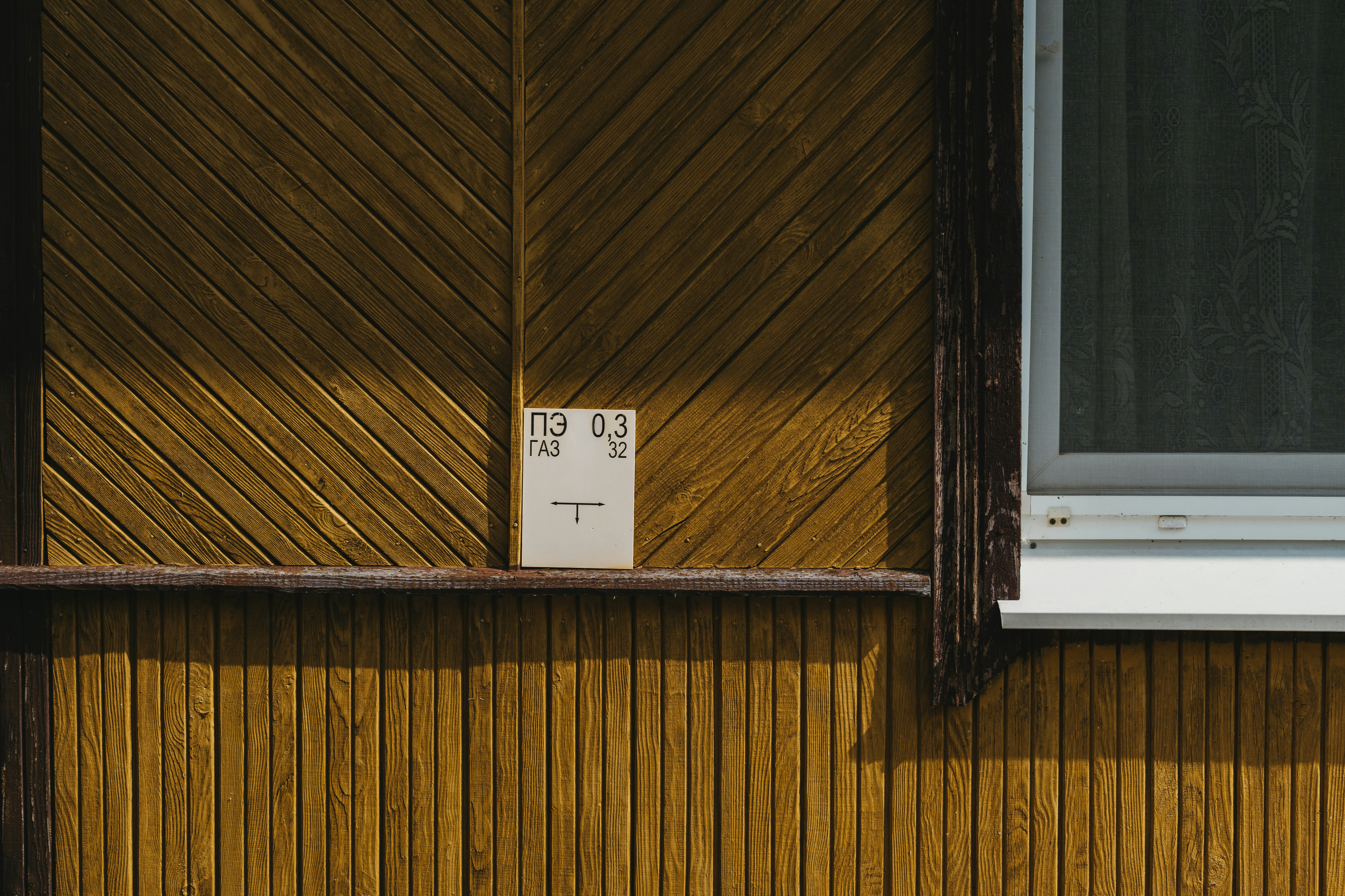 Sunlit Sign on Cedar Facade: Texture and Geometry in Warm Light