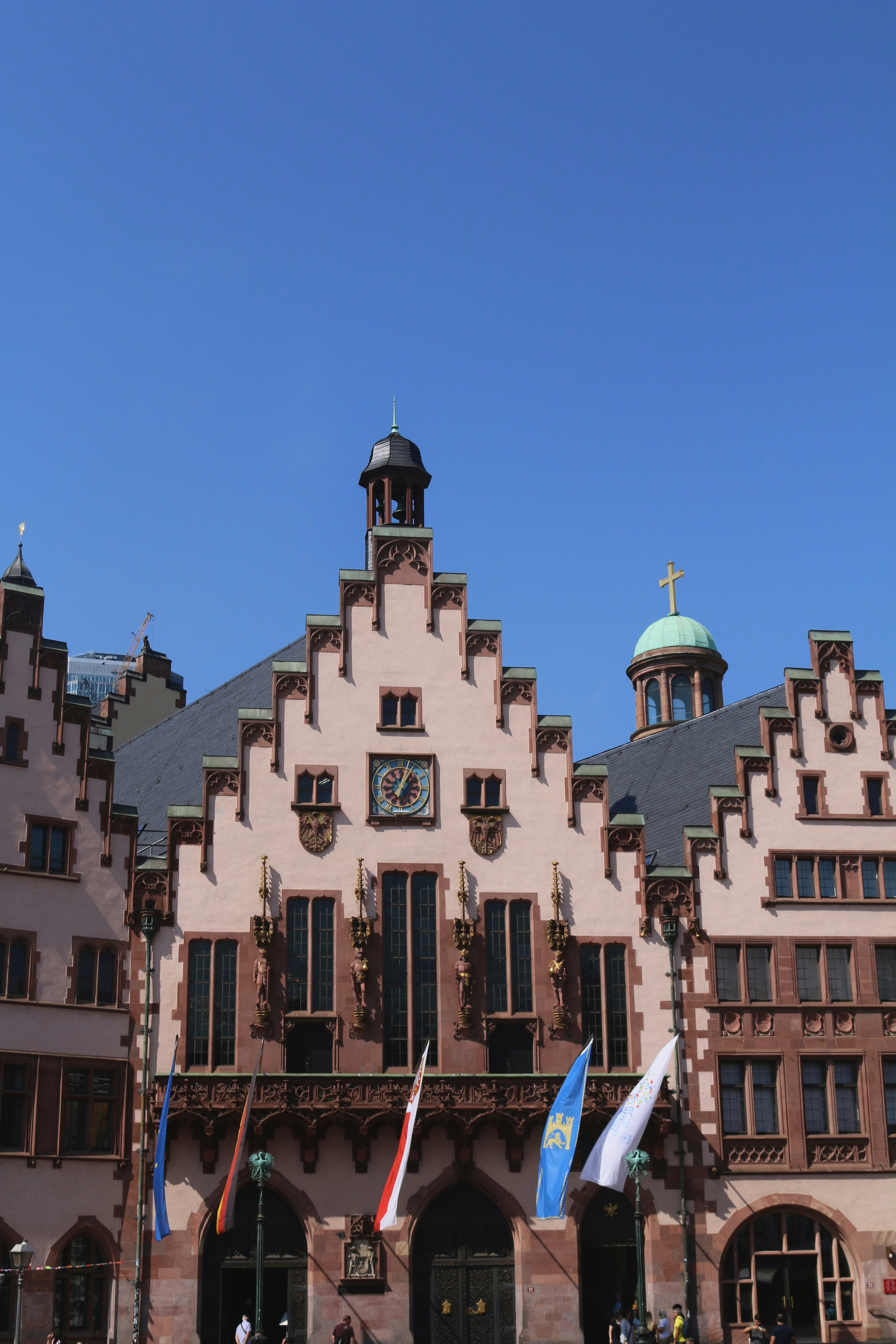Pink Gothic Town Hall: Flags and Arches Reach Toward a Clear Blue Sky