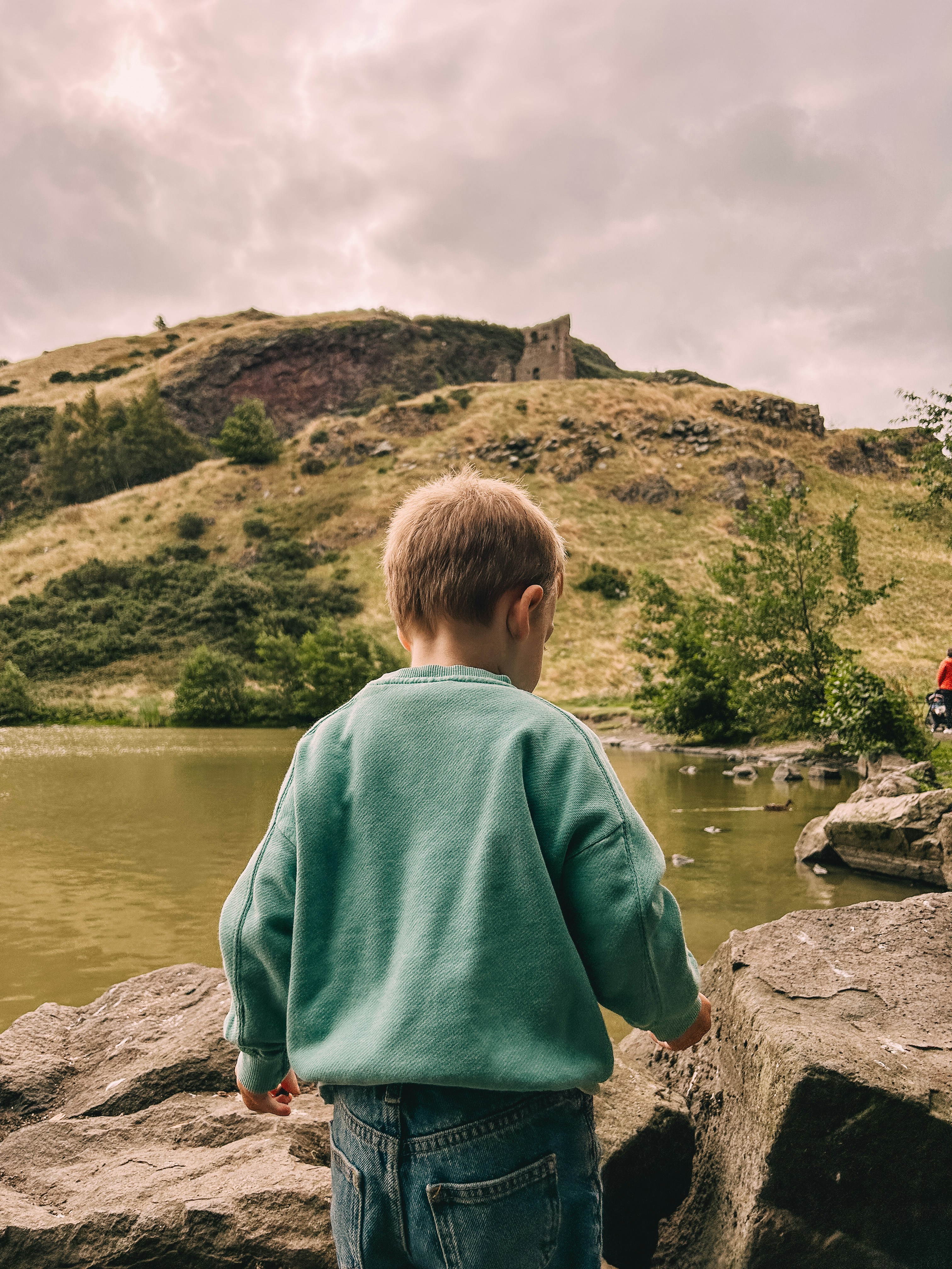 Quiet Frontiers: A Boy by the Lake with a Hilltop Ruin in the Distance