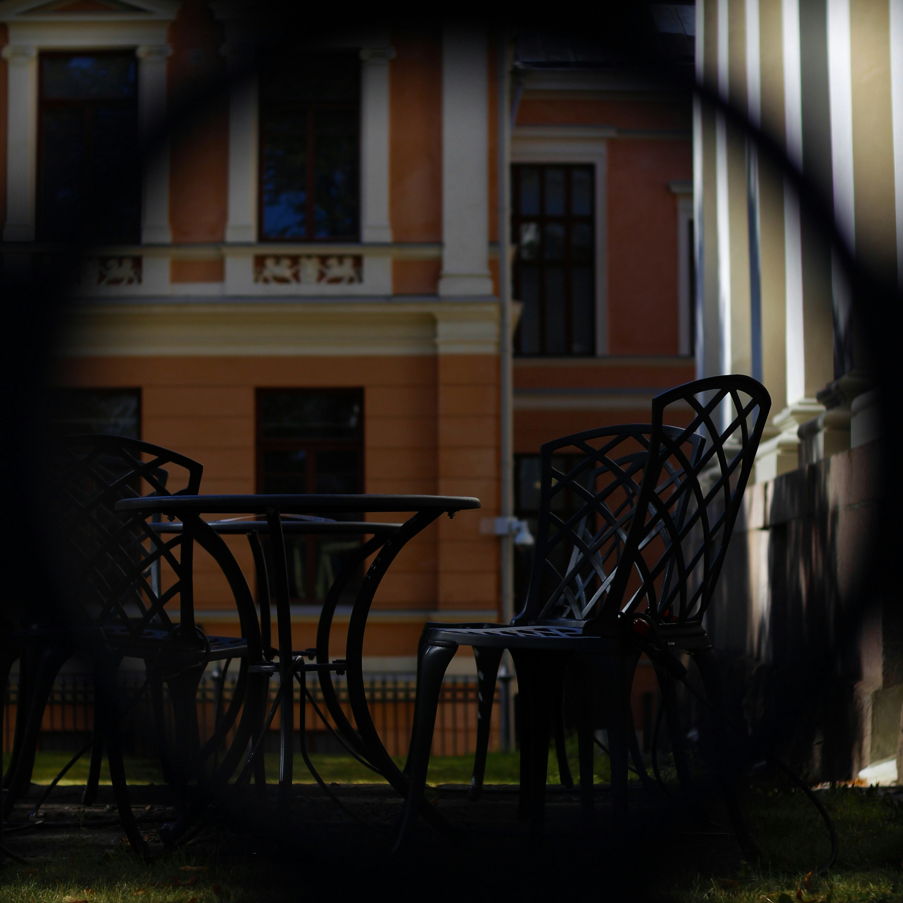 Ringed Evening: Silhouetted Tables Under Amber Facade