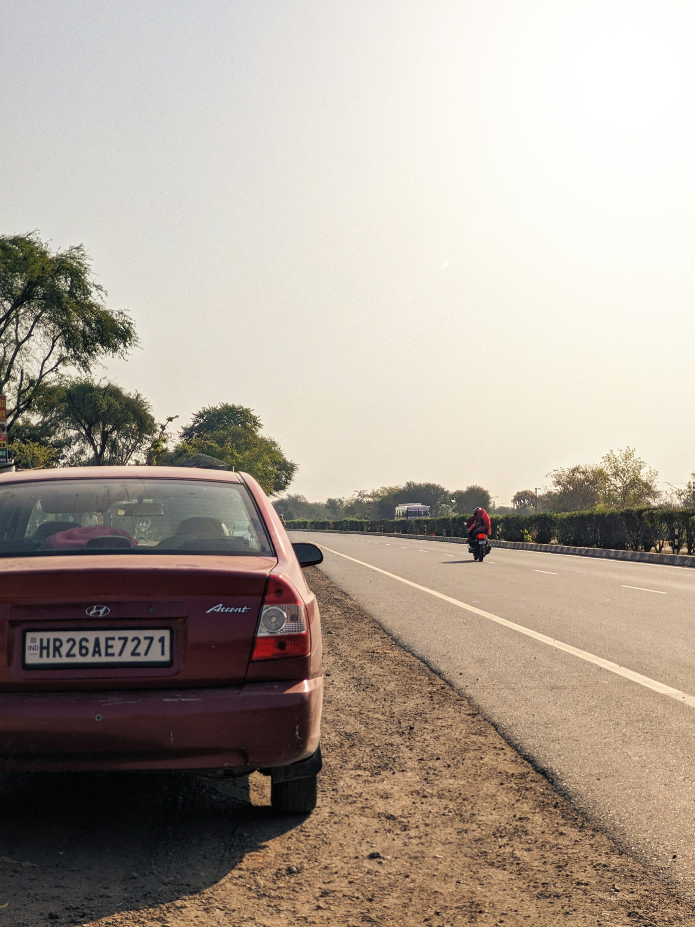 Dusty Highway Standstill: A Red Car and a Distant Rider