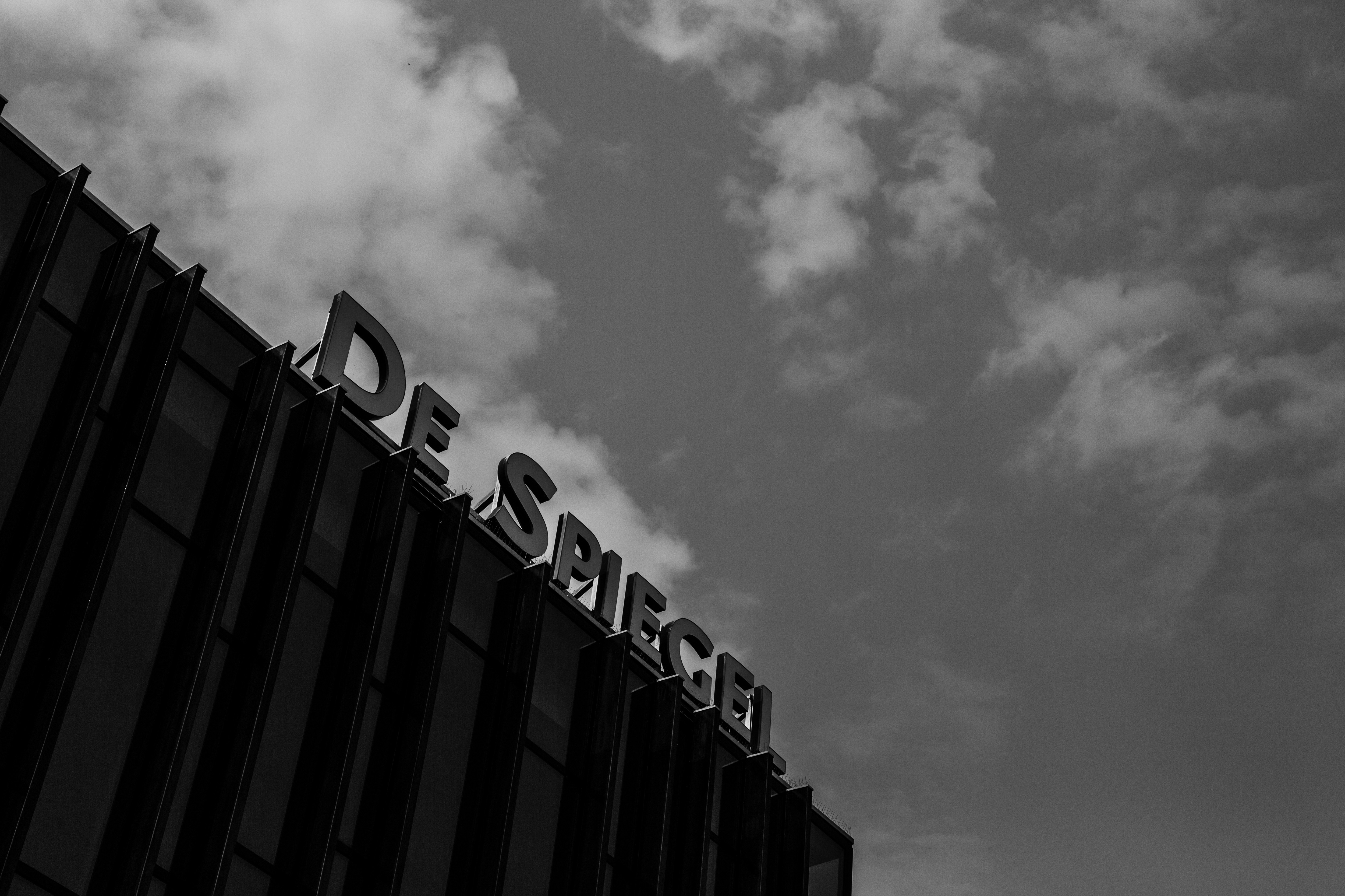 Black and white architectural sign contrasts with dramatic clouds above.