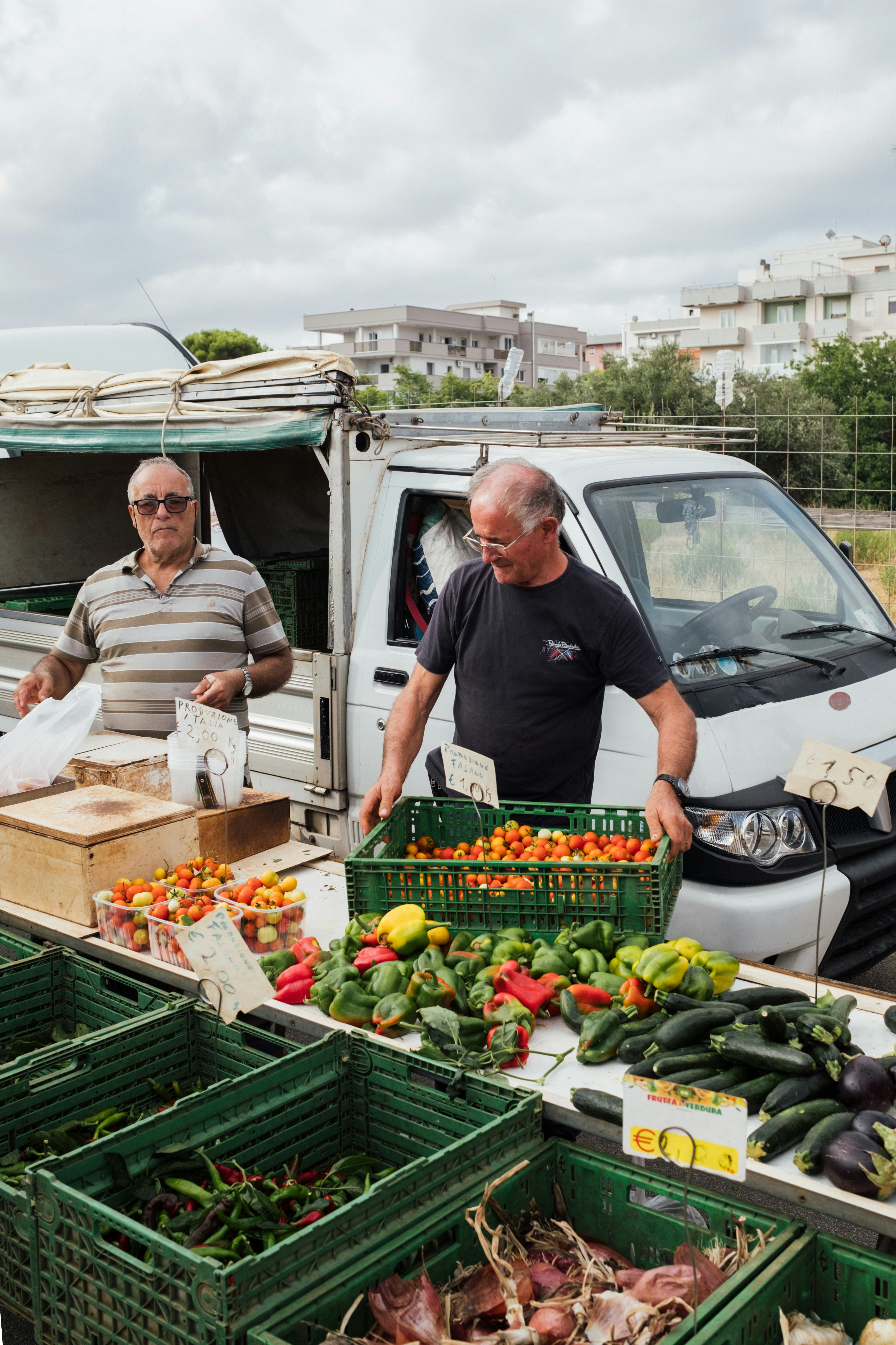 A group of men standing around a table filled with vegetables photo ...
