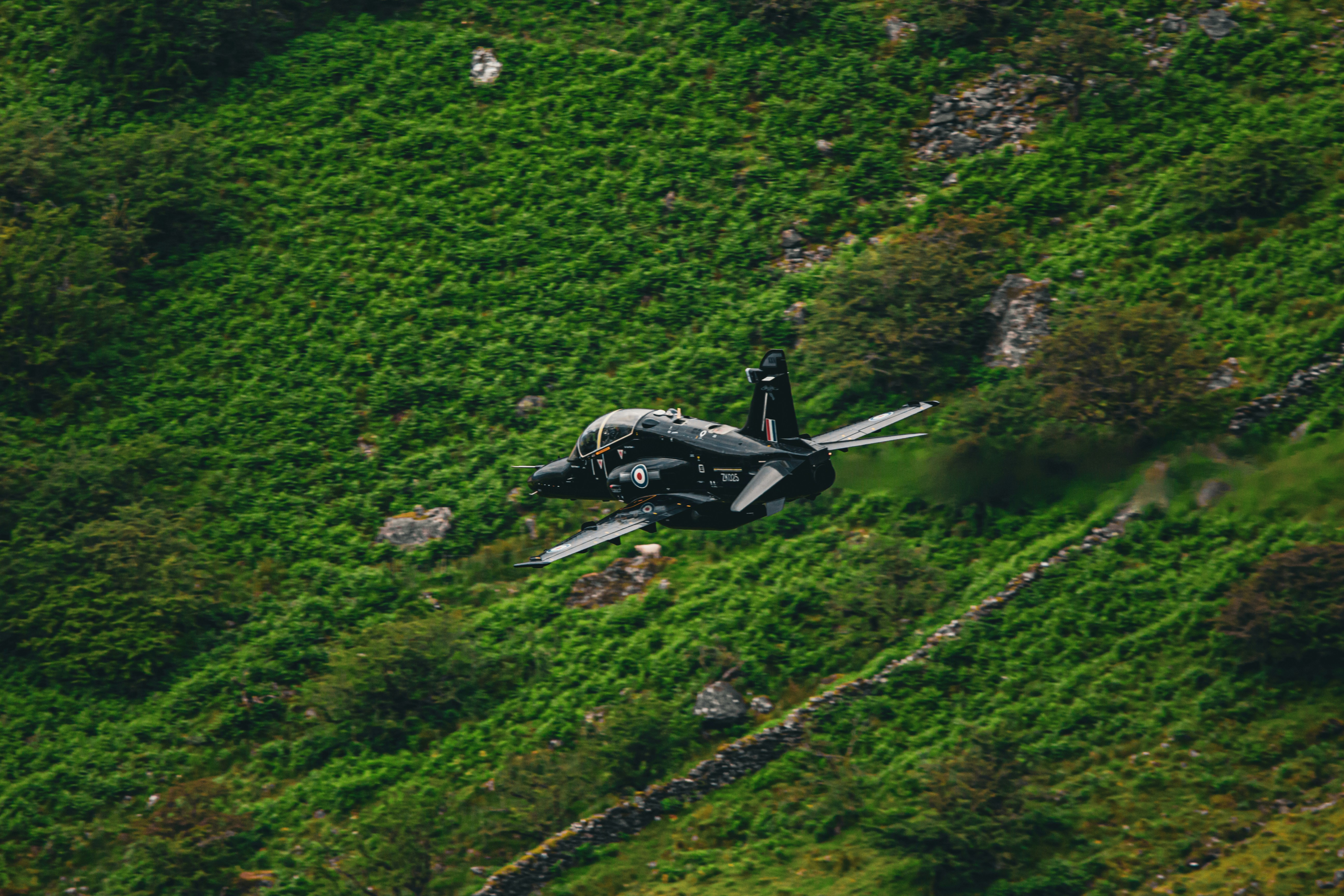 Dark Helicopter Gliding Over Emerald Ridges