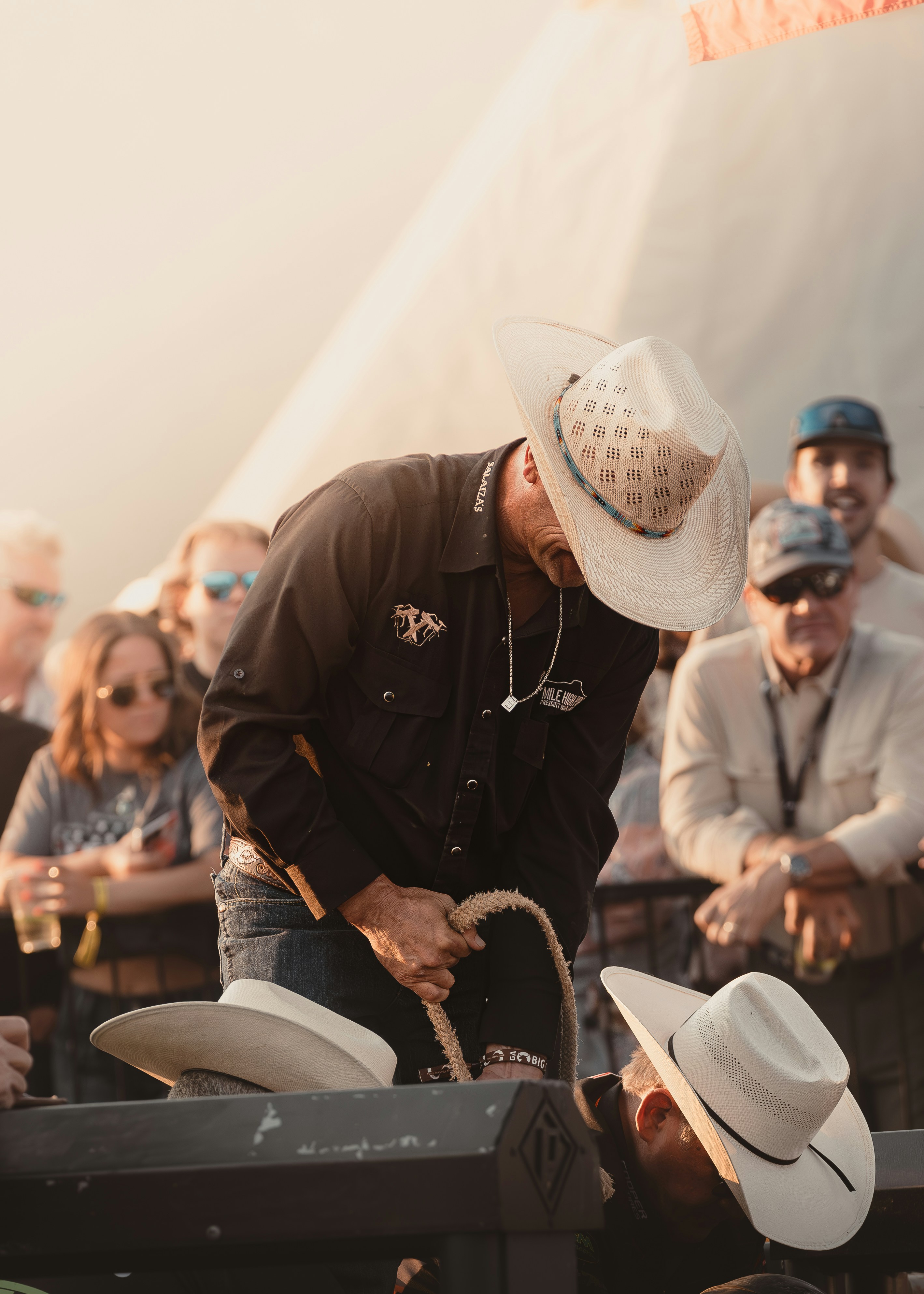 Hat in Focus: A Cowboy Bends Into the Crowd at a Rustic Outdoor Jam