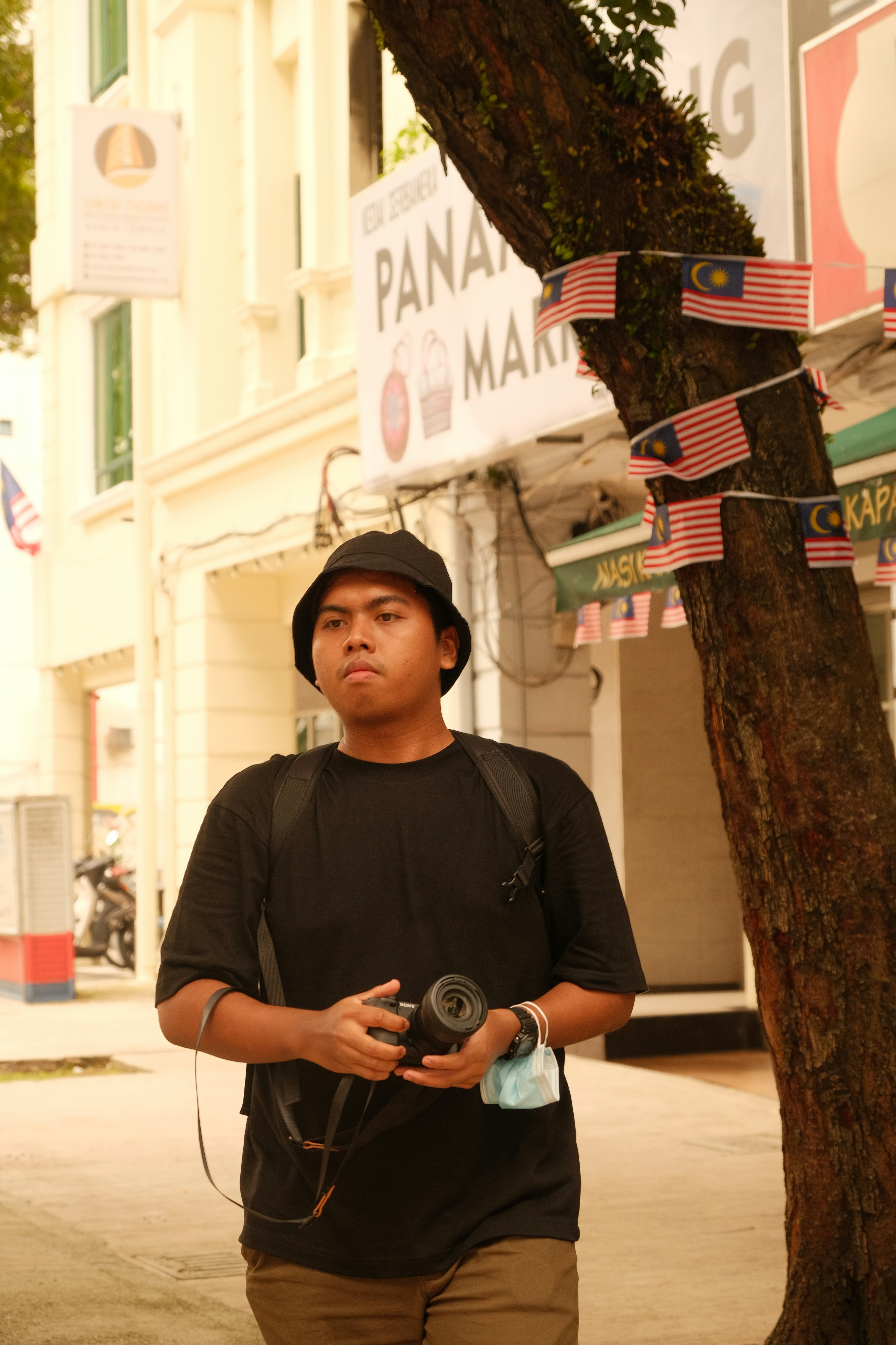 Under the Flags: A Street Photographer Pauses with Camera in Hand