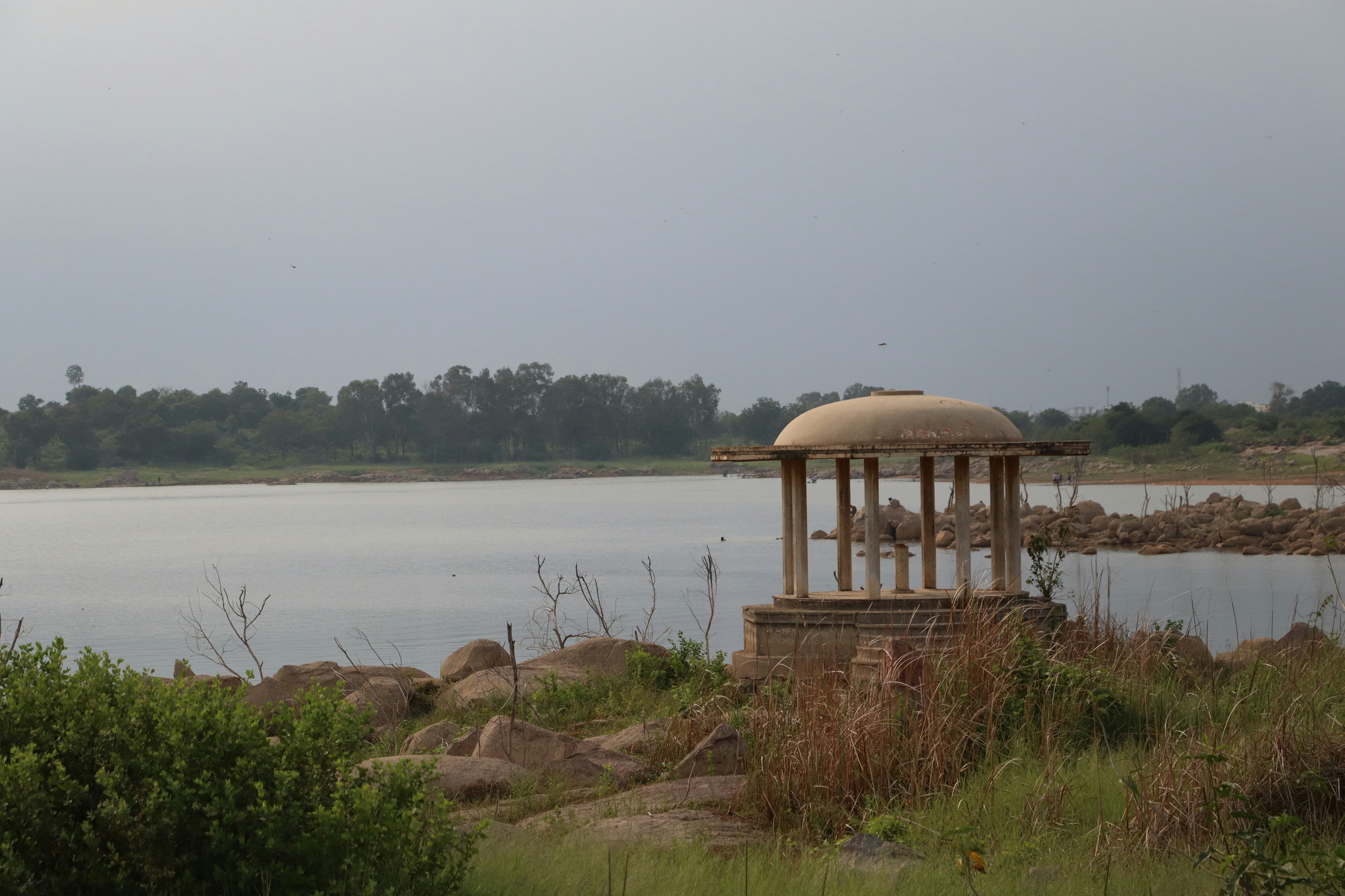 Riverside Gazebo on a Rocky Shore under an Overcast Sky