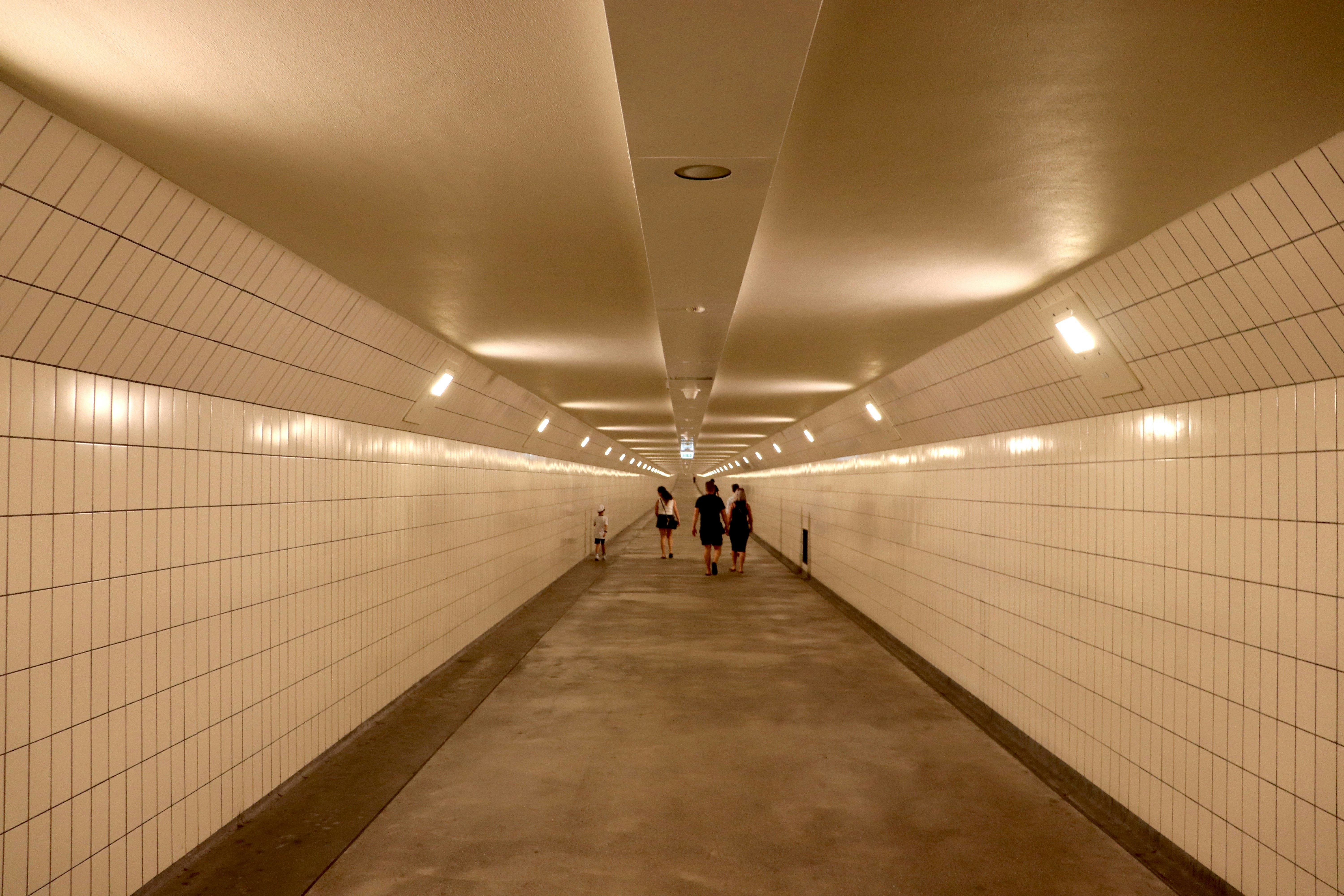 Two people walking down a long hallway in a subway photo – Free ...