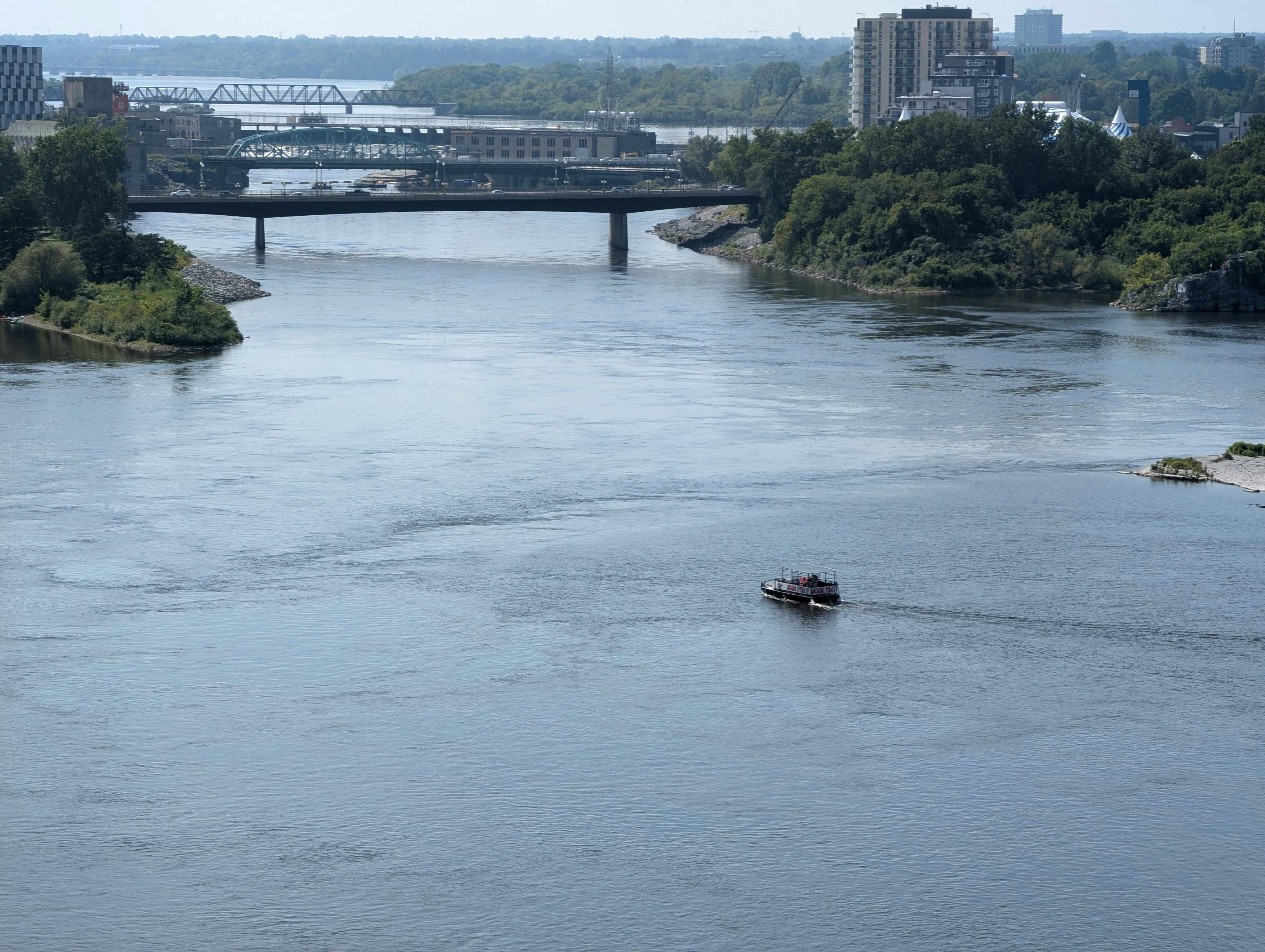 A boat traveling down a river next to a bridge photo – Free Building ...
