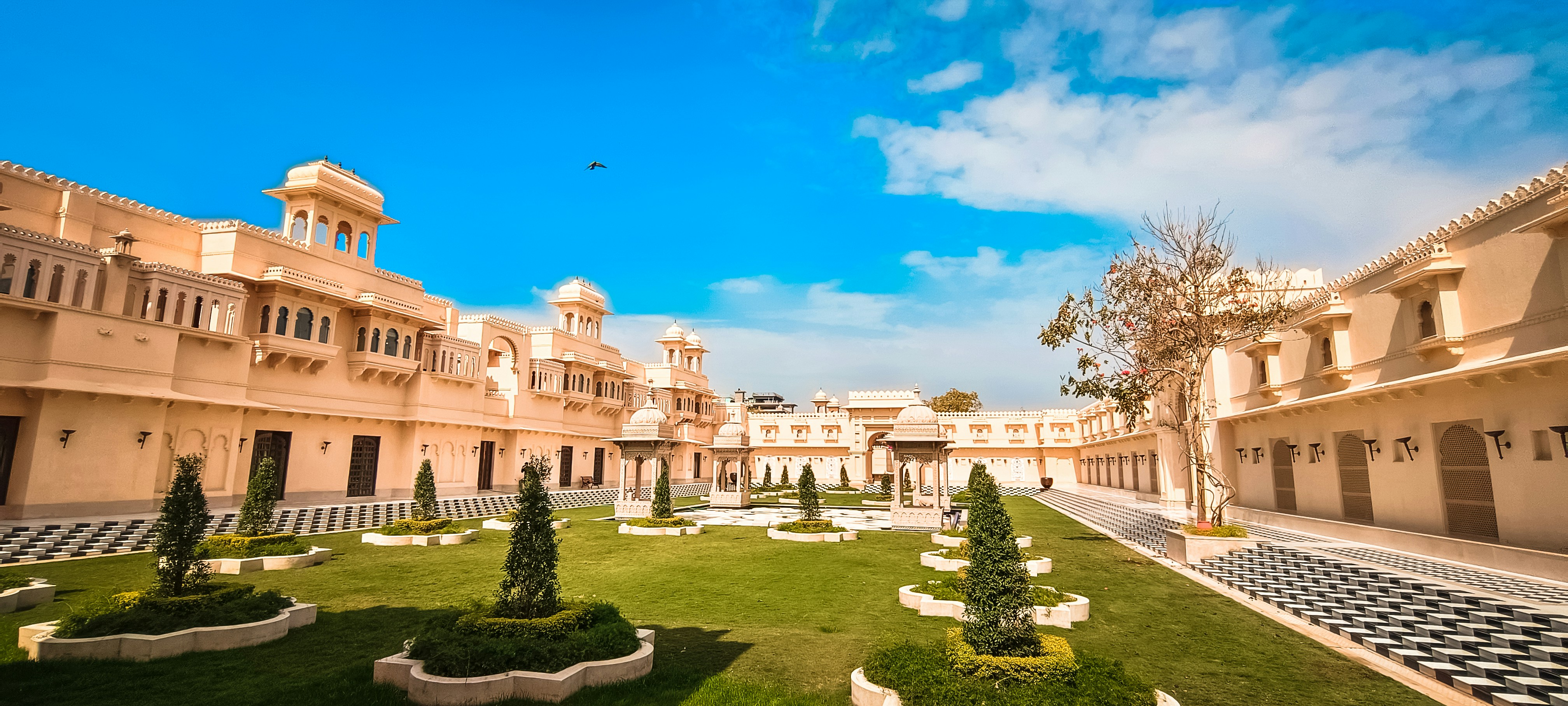 Expansive courtyard surrounded by ornate beige buildings under a vibrant blue sky.